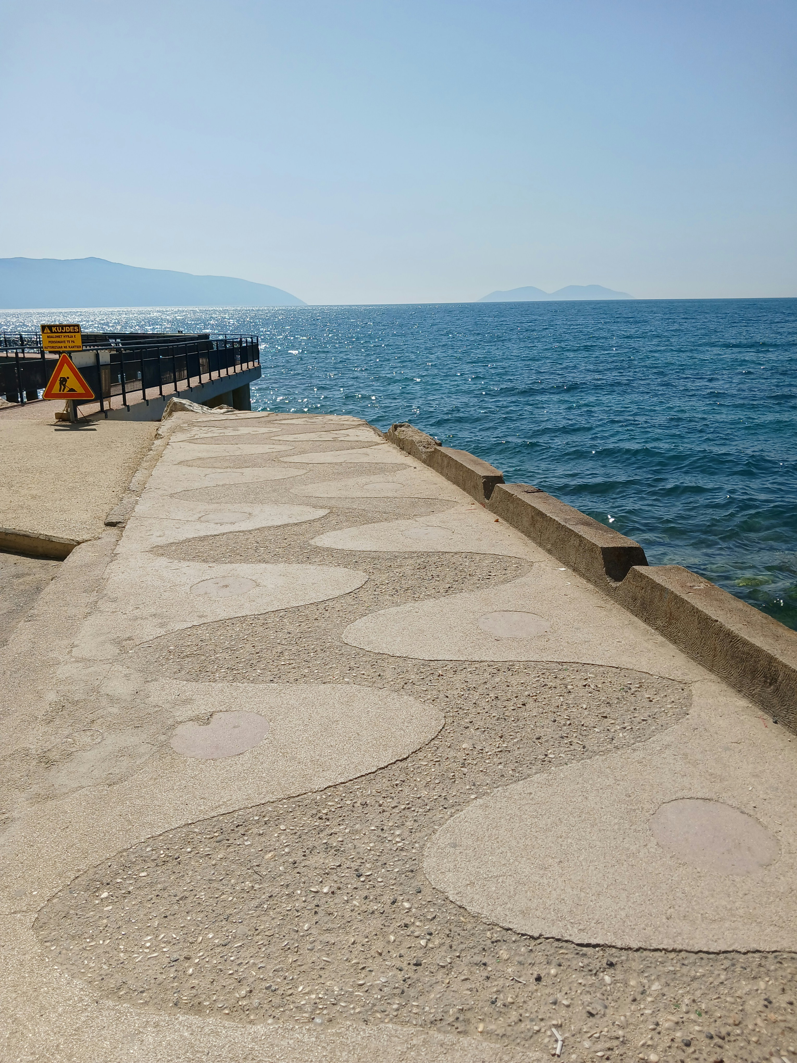 A long concrete walkway next to a body of water