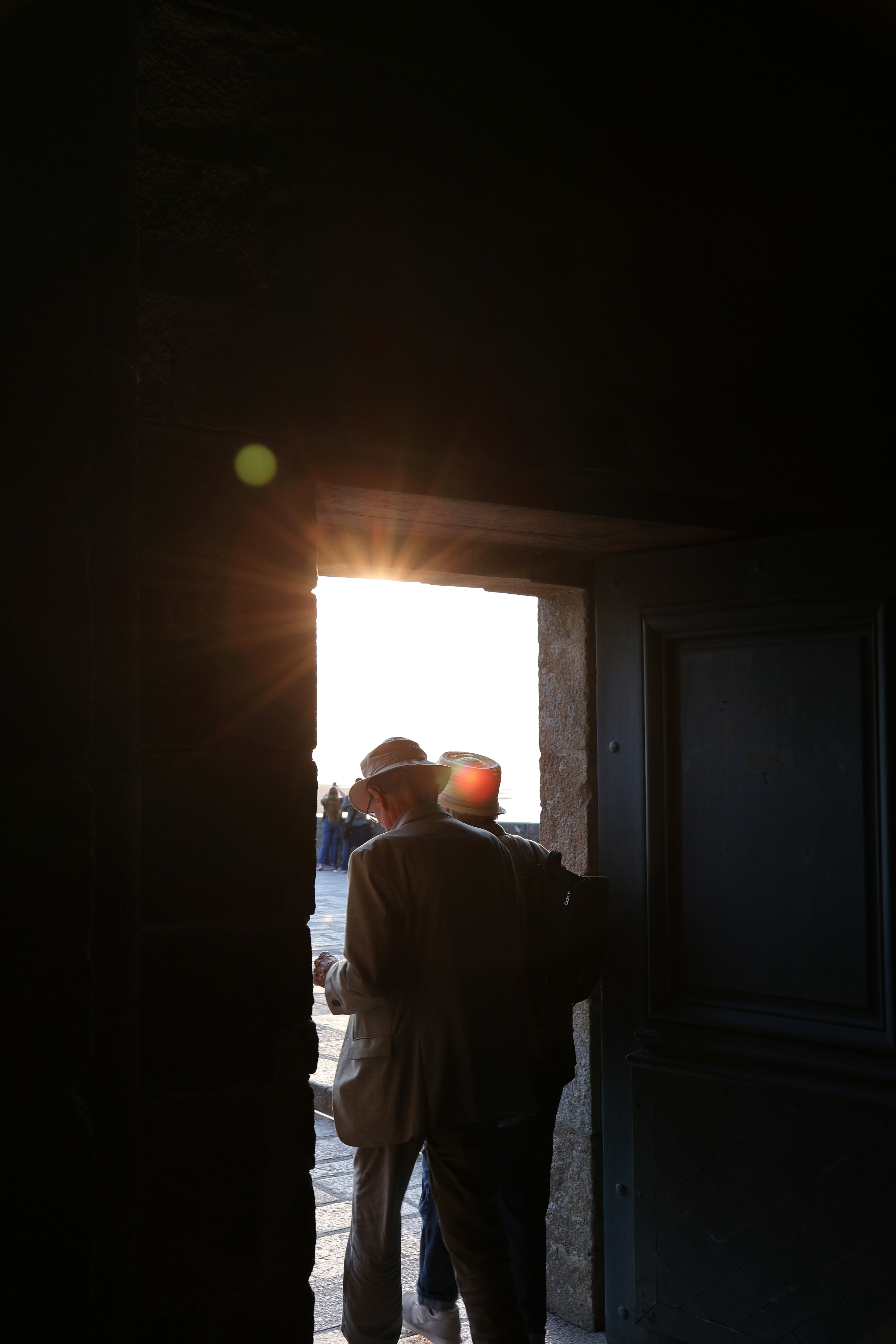 Threshold of Light: Two Figures in a Dim Doorway Embrace the Sun