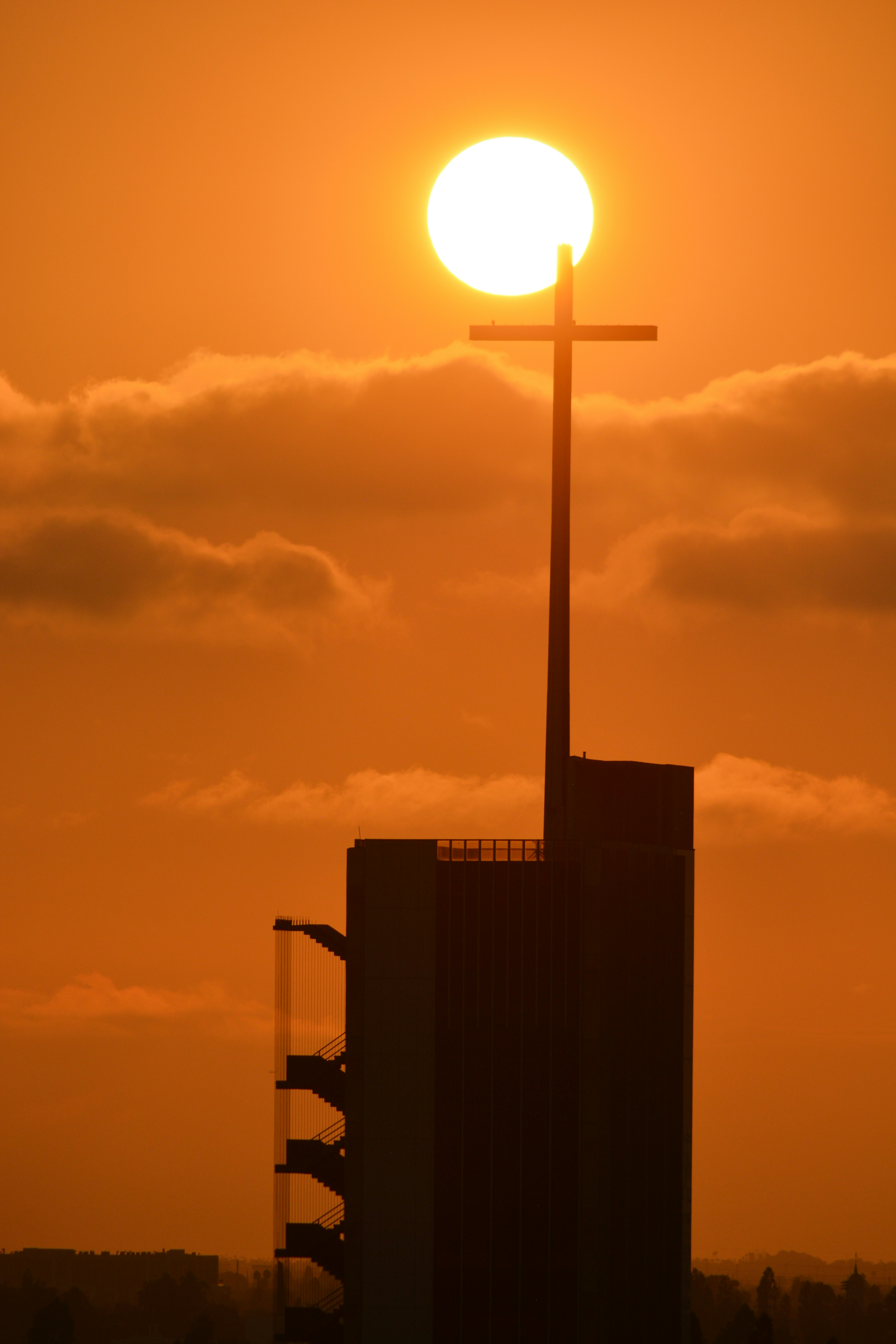 Sun-Halo Over the Cross: Dusk Silhouette on a City Tower