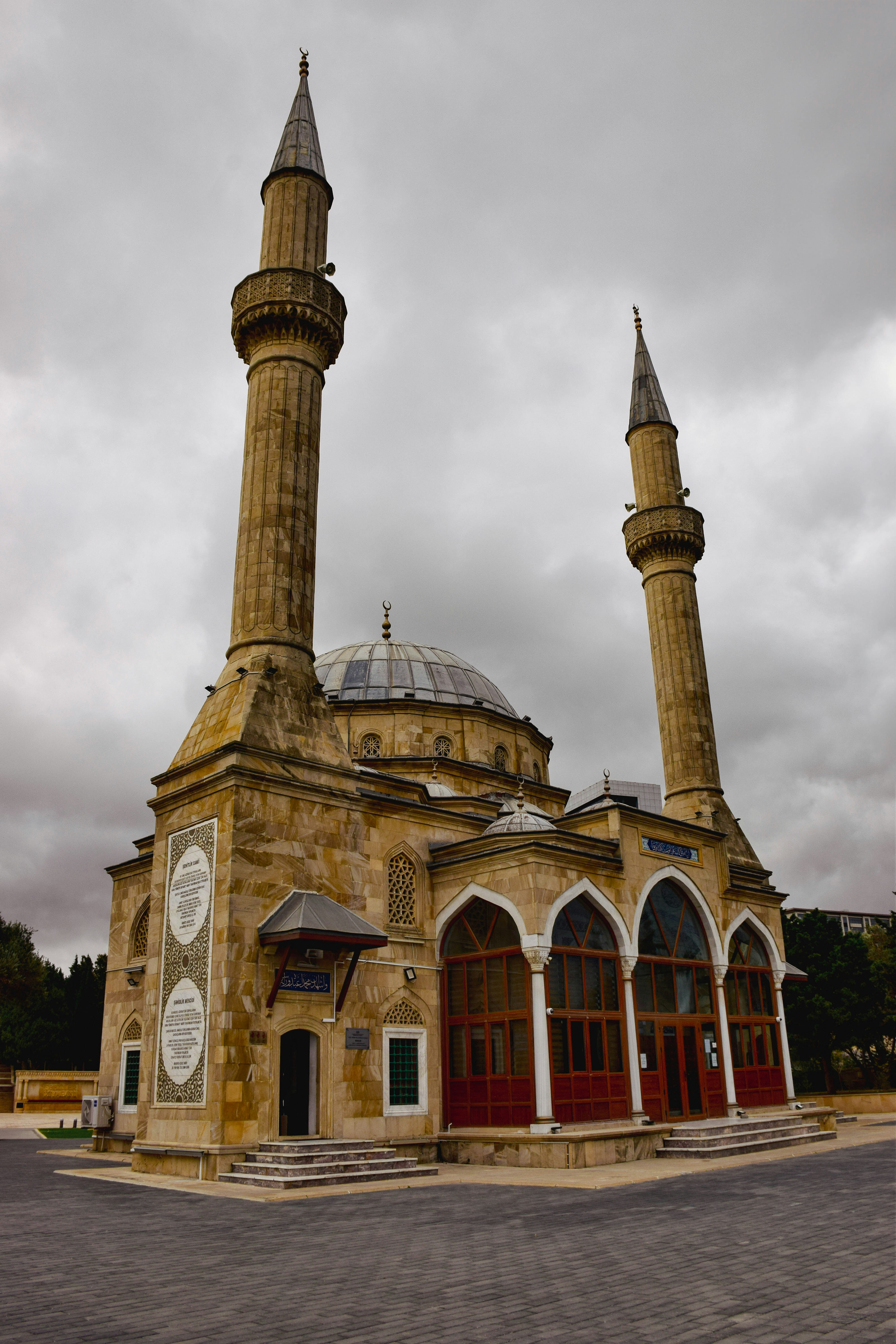 Stone Mosque Under Cloudy Skies: Twin Minarets Framing a Grand Facade