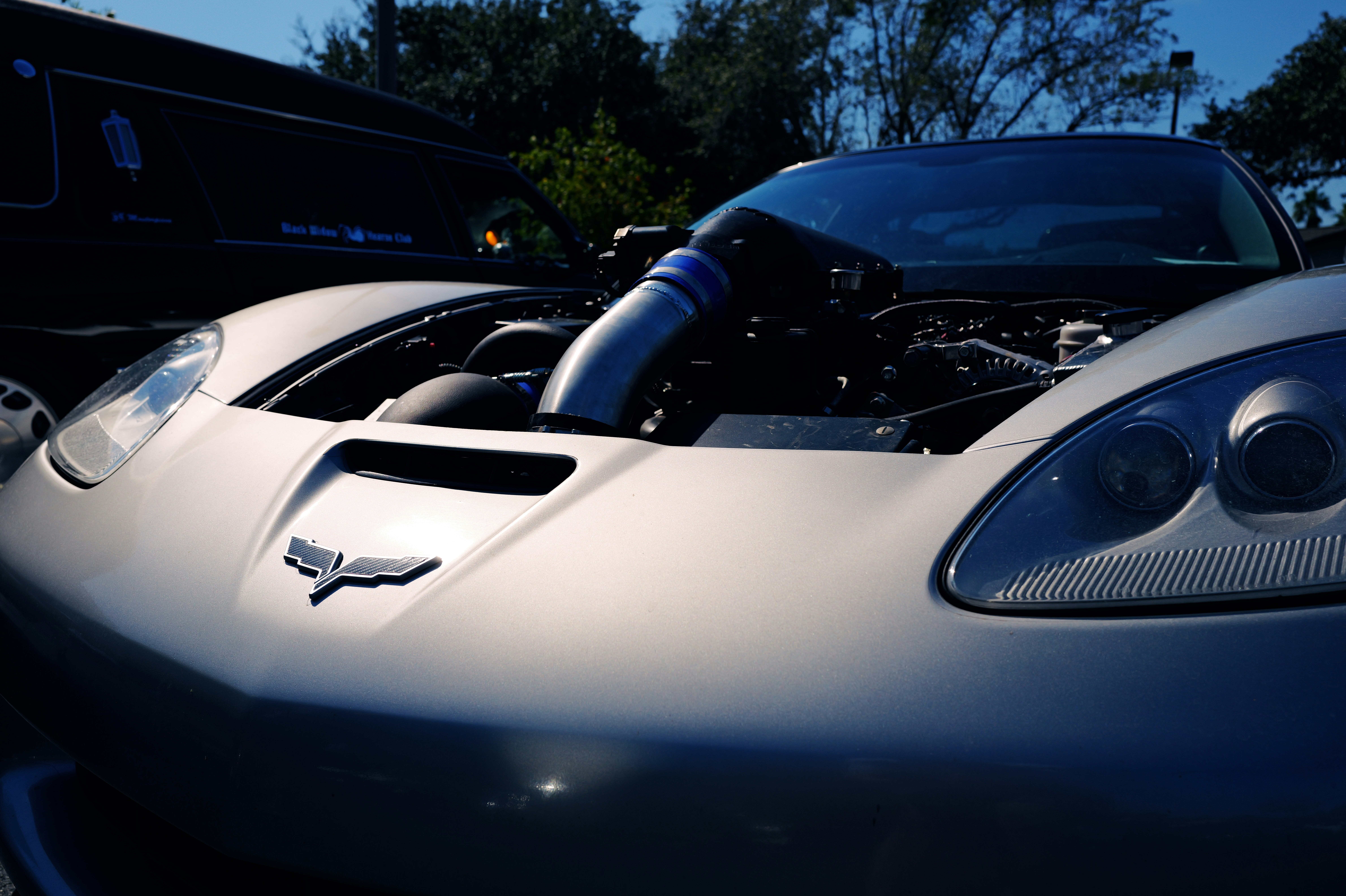 Close-Up of a Corvette's Engine Bay: Blue Intake Against Silver Curves