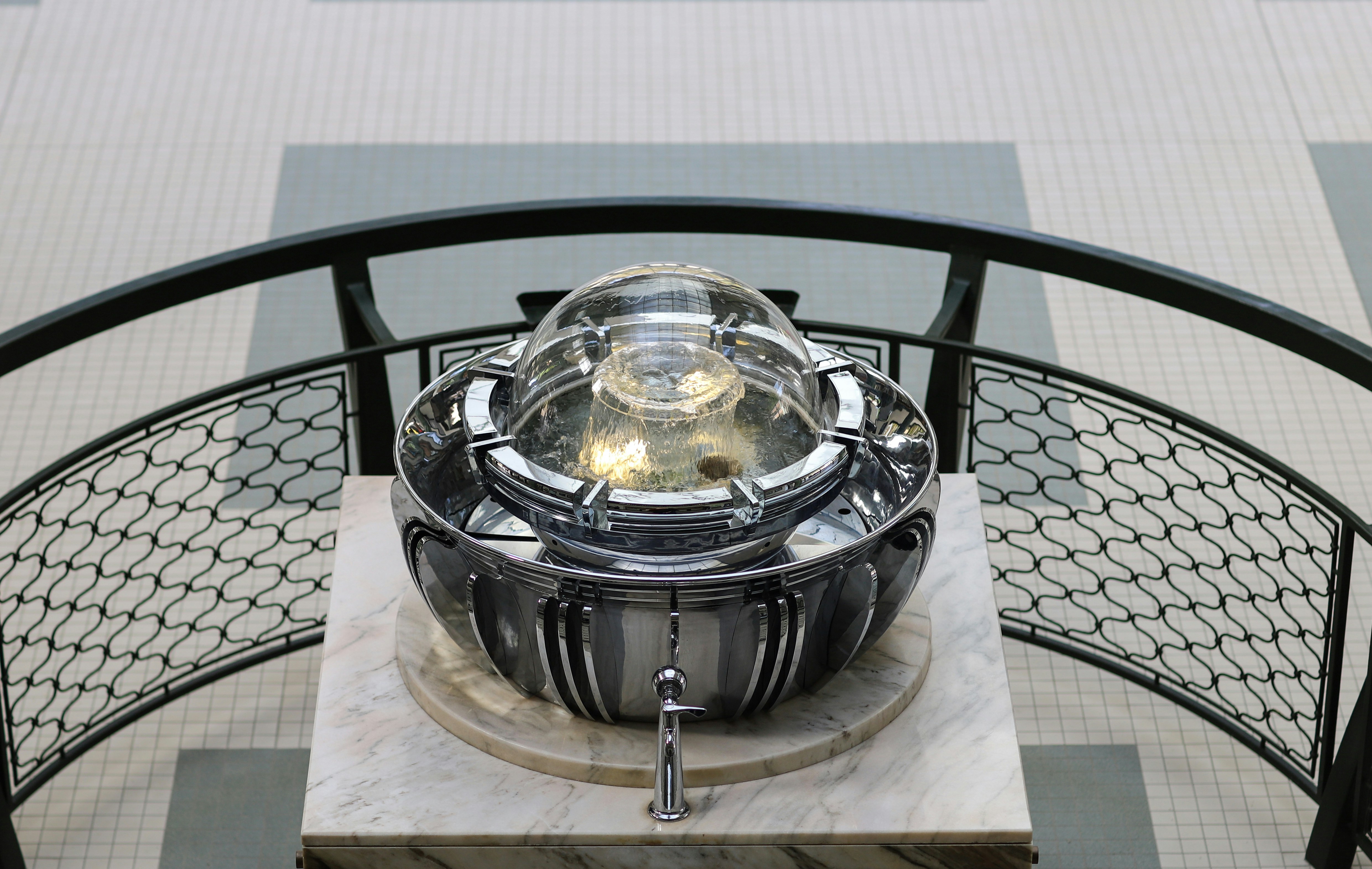 Orbital Glow: Glass Globe Fountain Encircled by a Circular Iron Rail