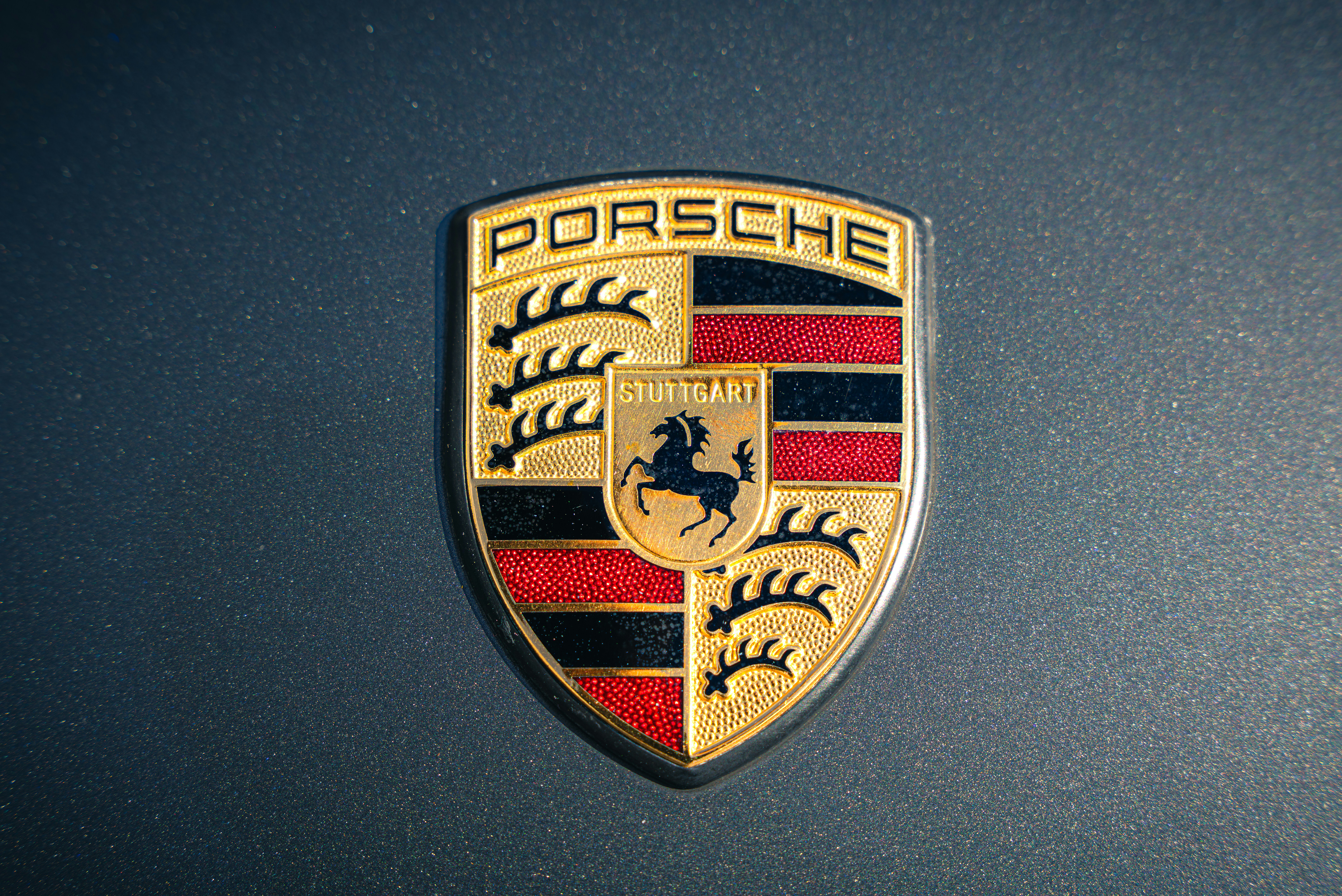Glinting Crest: Porsche Emblem Anchored in Deep Blue Metallic