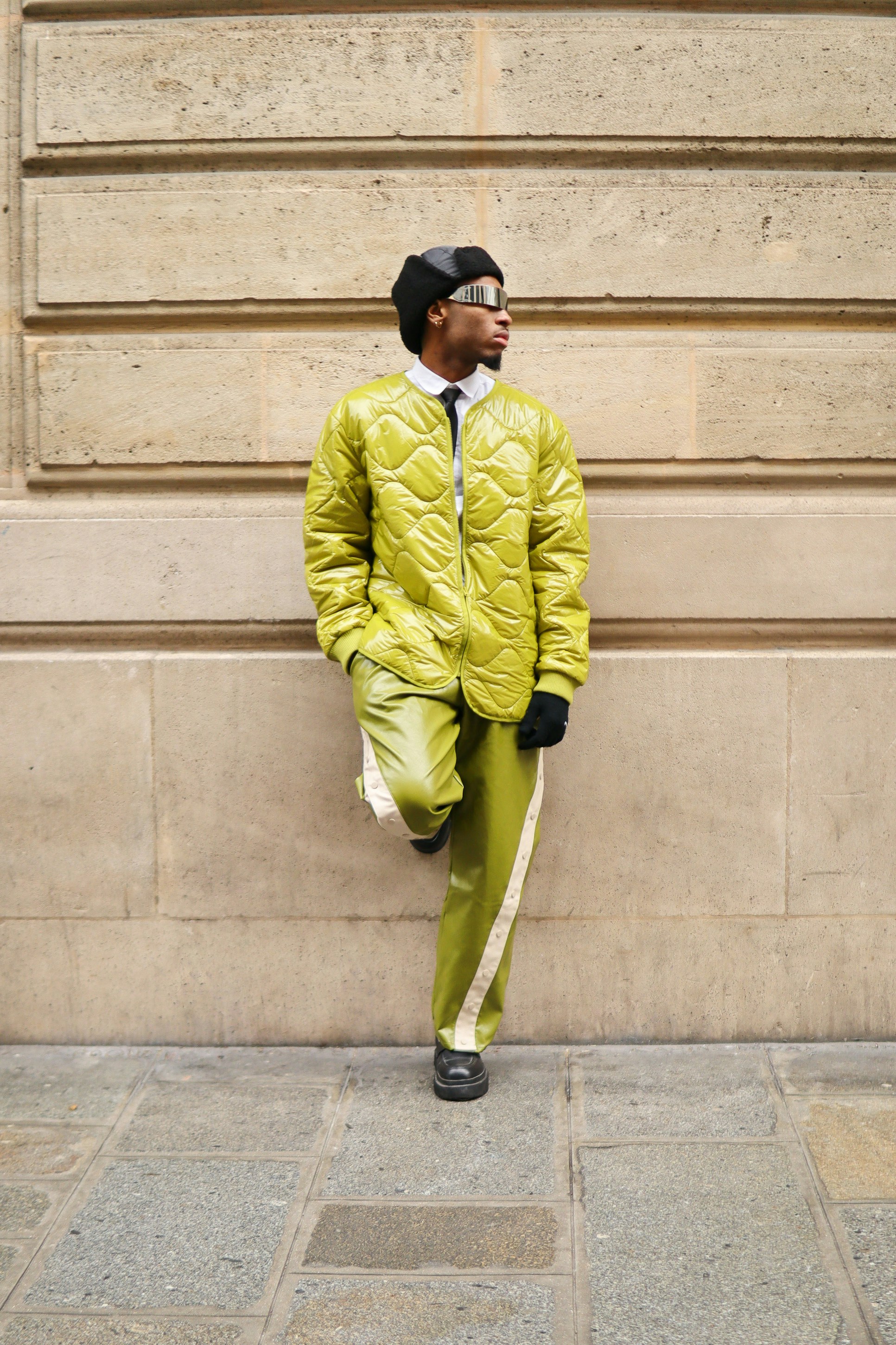 Neon Olive: street style pauses against a stone wall