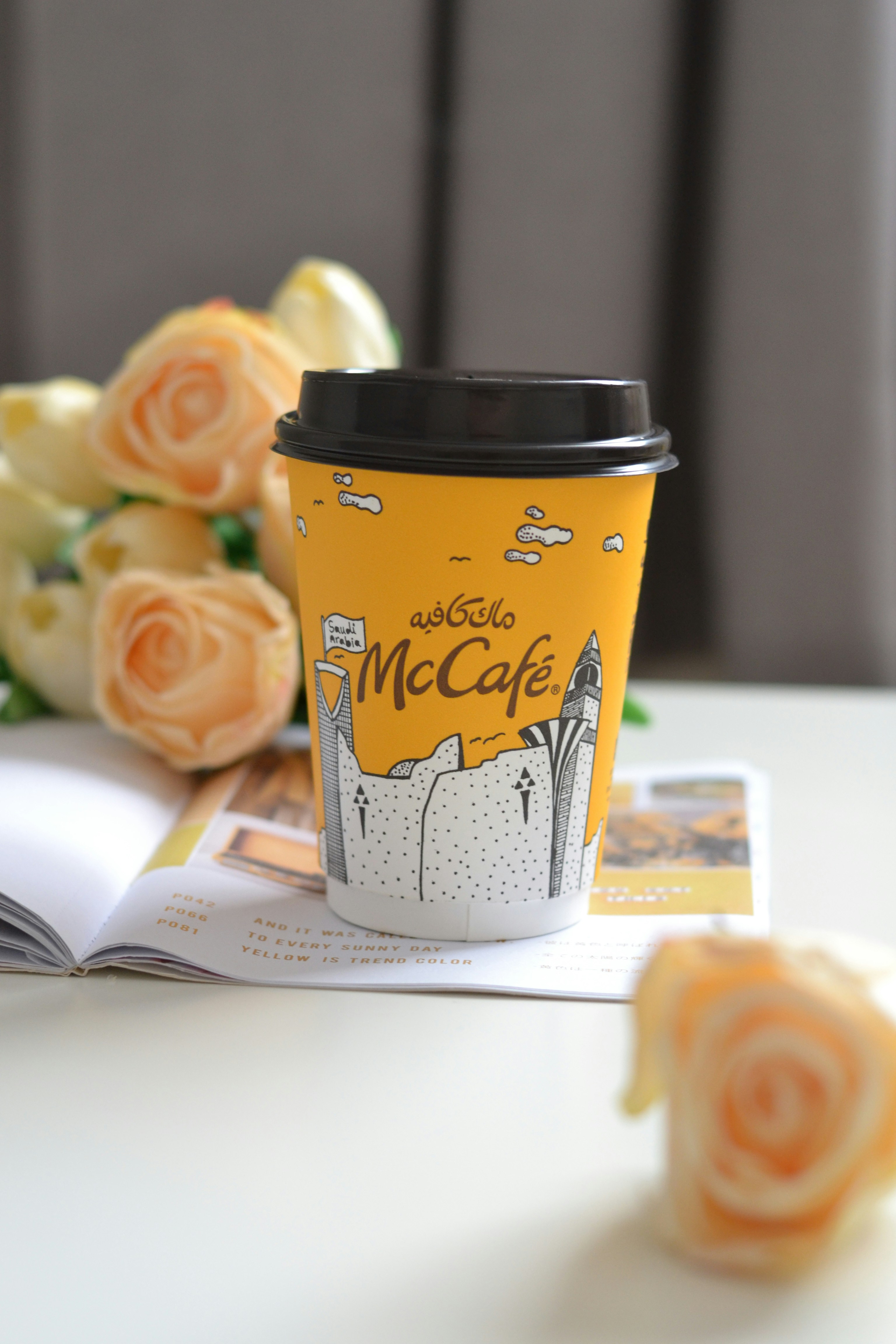 McCafé in Bloom: A Sunny Cup Among Peach Roses and a Graphic Skyline