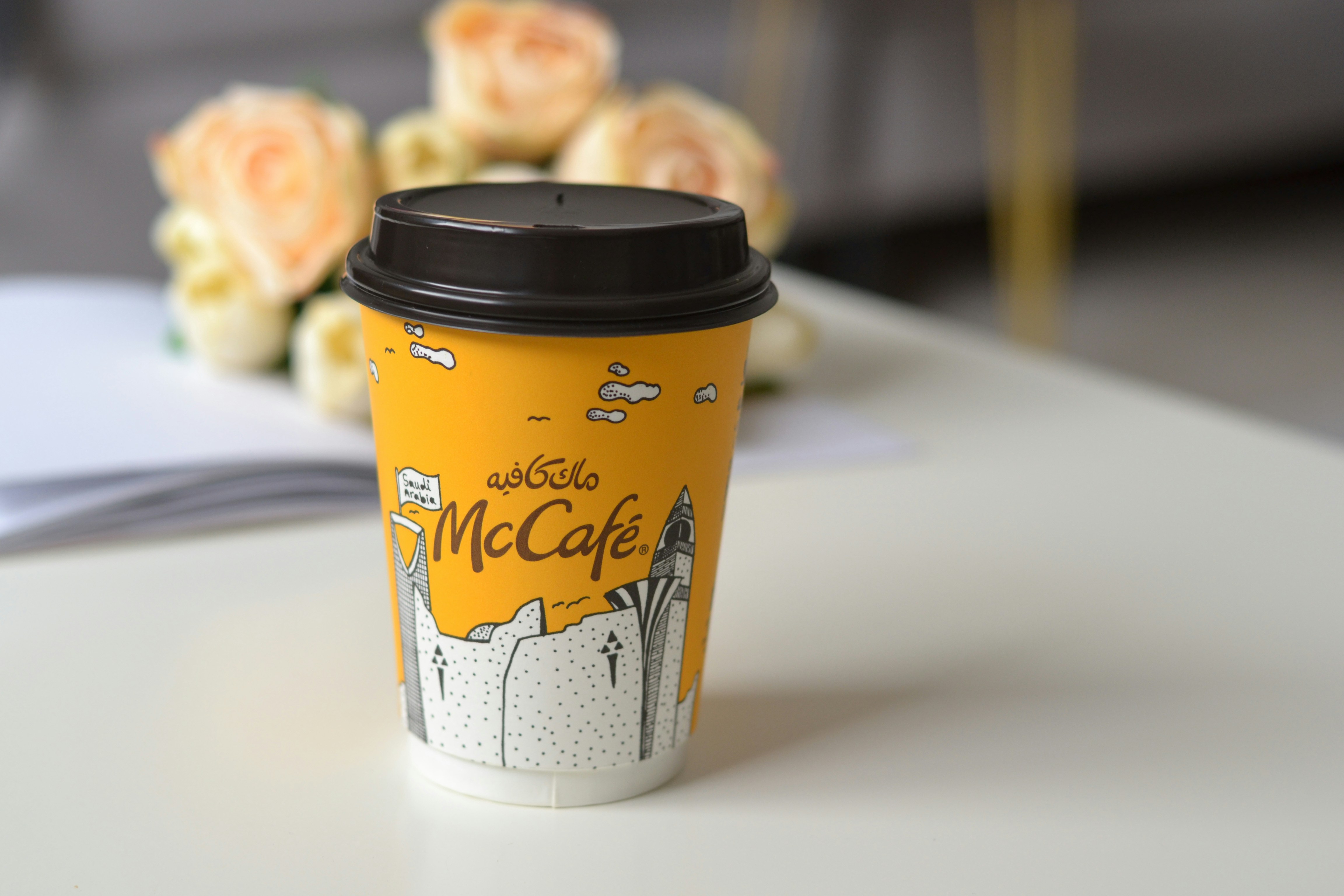 Sunlit McCafé Cup on a White Surface with a Rosy Blur