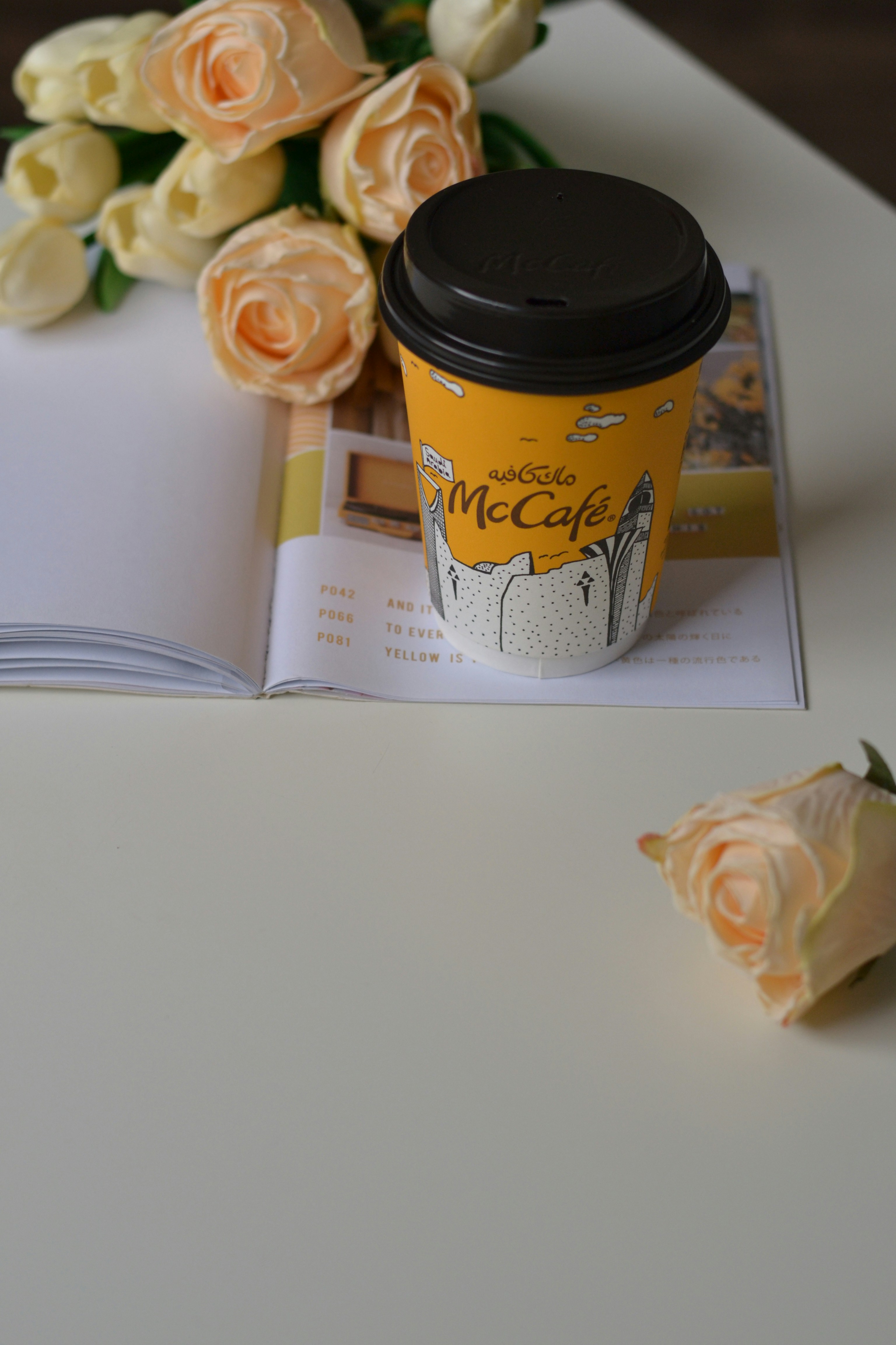 Yellow Cup of Coffee on Open Magazine with Soft Bouquets