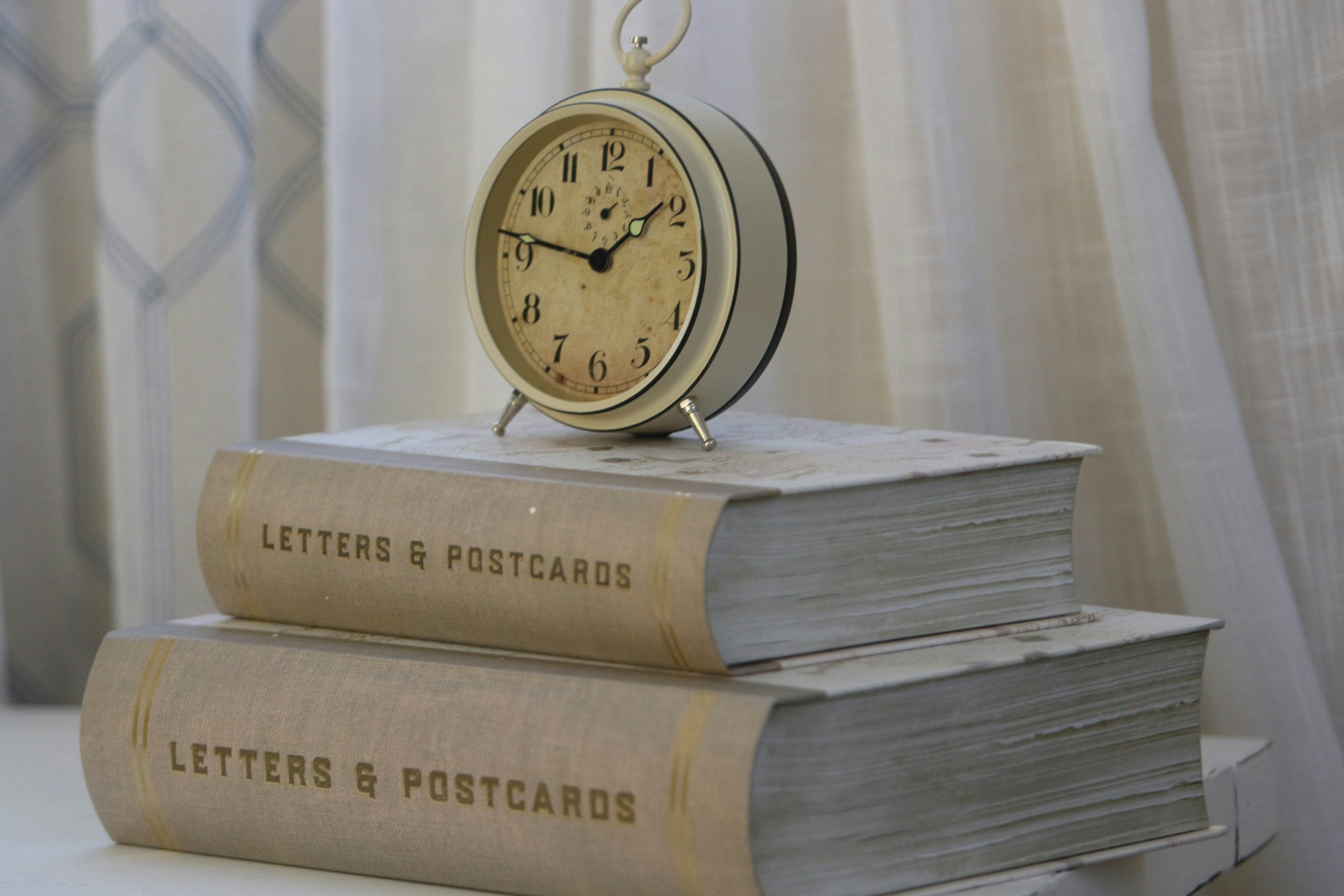 Timekeeper on Paper: A Vintage Clock Resting Above A Stack of Letters & Postcards