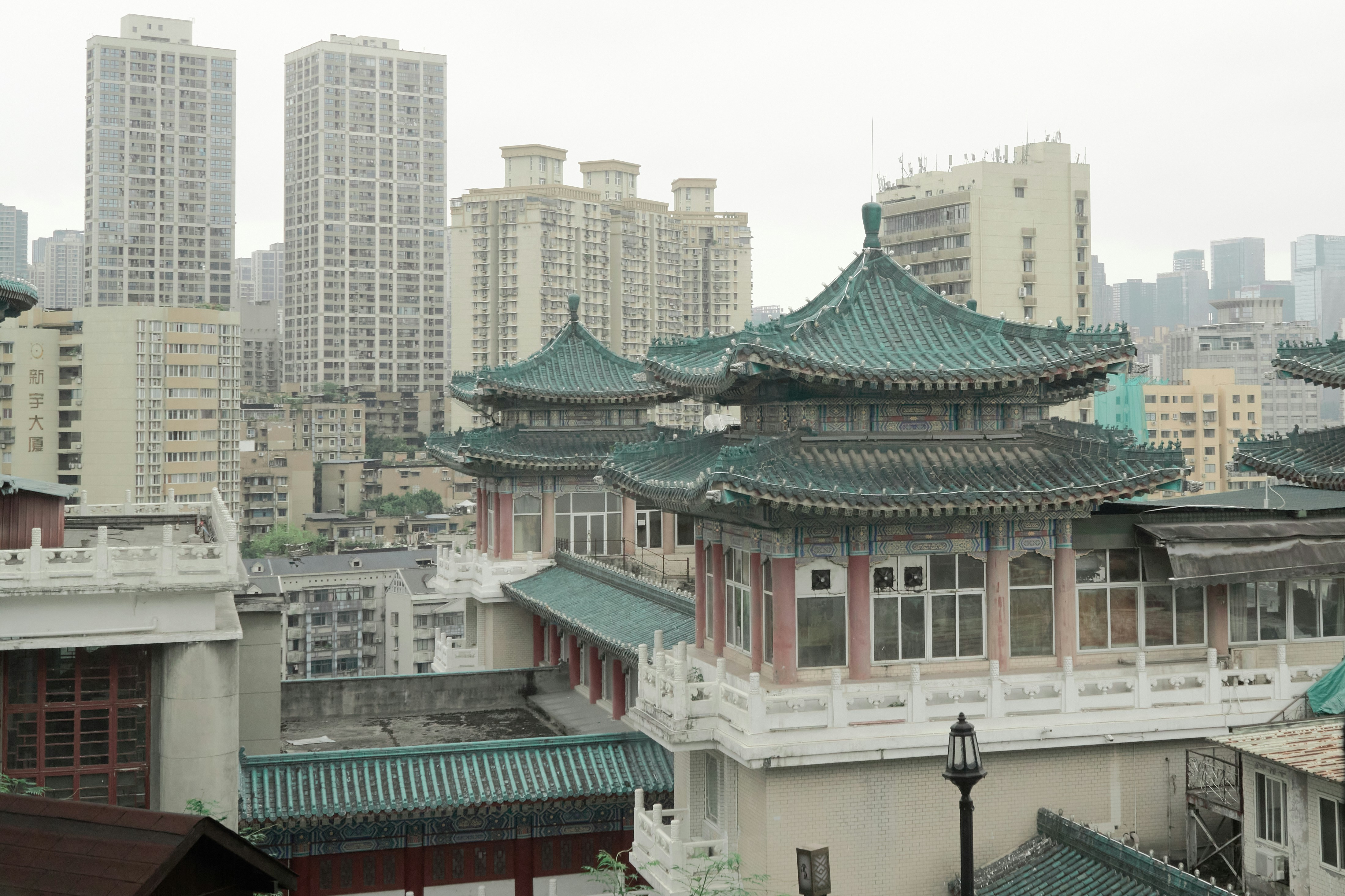 Teal-Tiled Pavilion Framed by a City of Towers