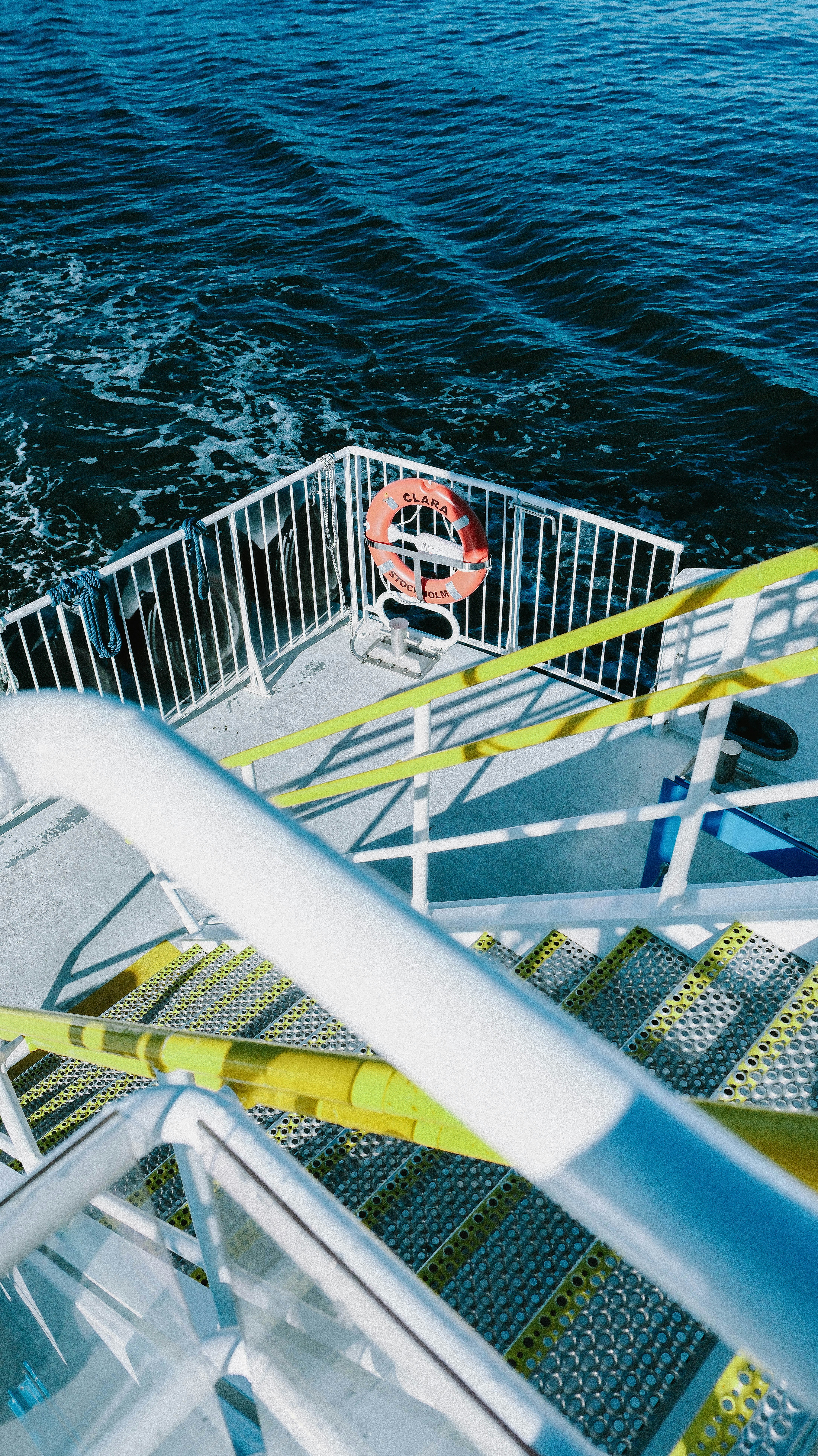 Neon Orange Lifebuoy Framed by Yellow Rails on a Ferry Stairwell