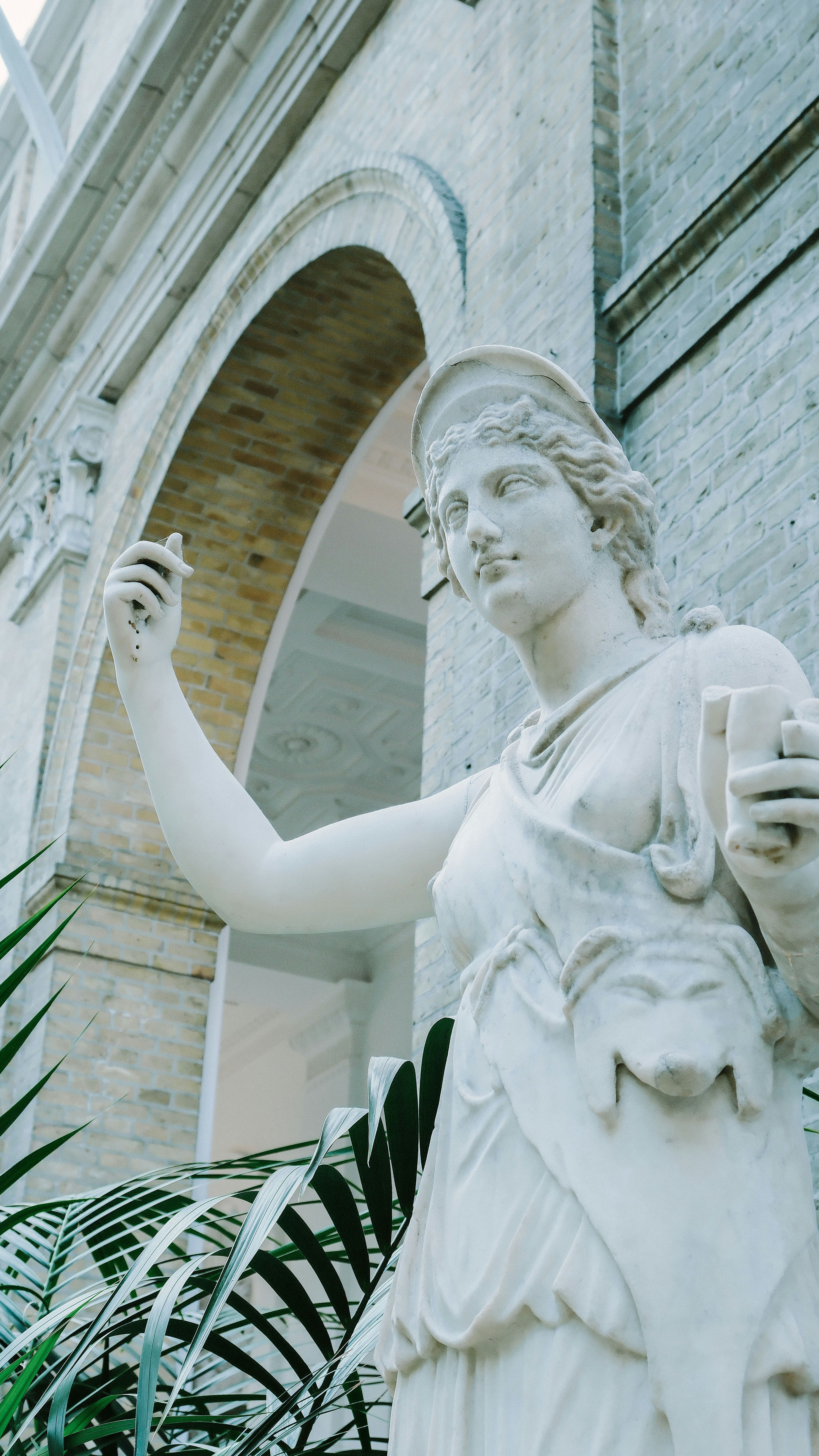 Marble Muse Beneath Brick Arches in a Quiet Atrium