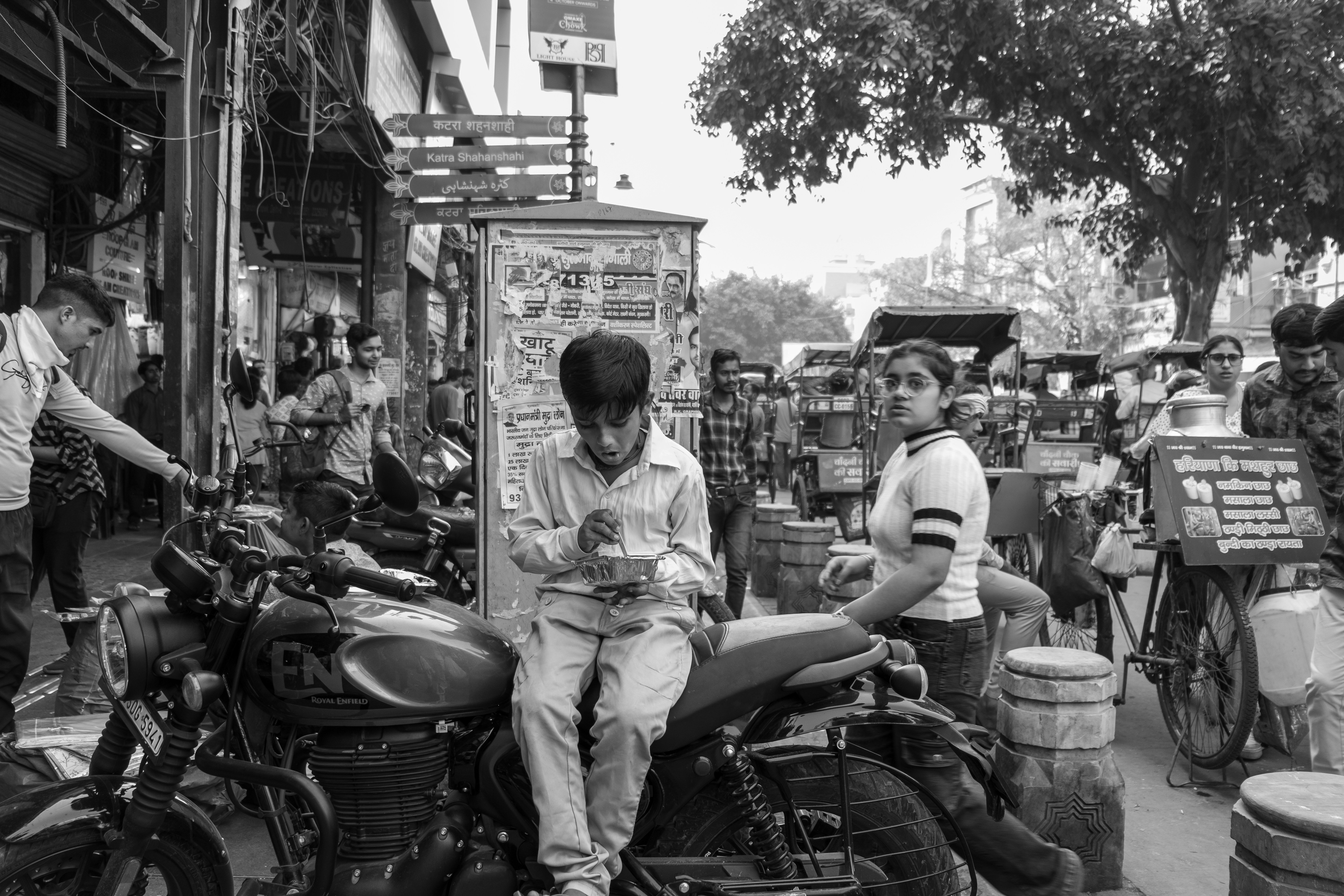 Quiet Contemplation in a Bustling Market: Teen on a Parked Motorcycle