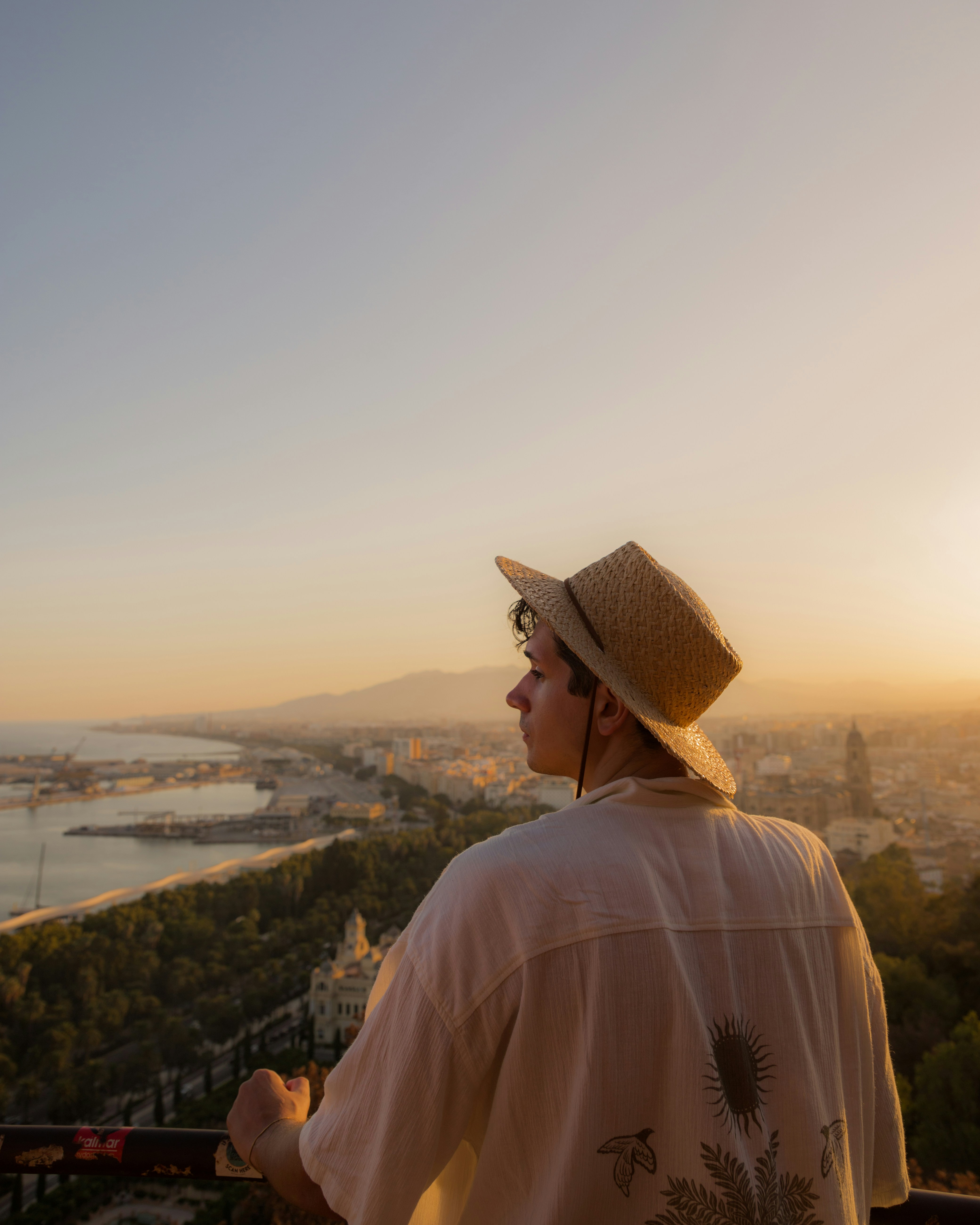 A man wearing a hat looking out over a city photo – Free Hat Image on ...