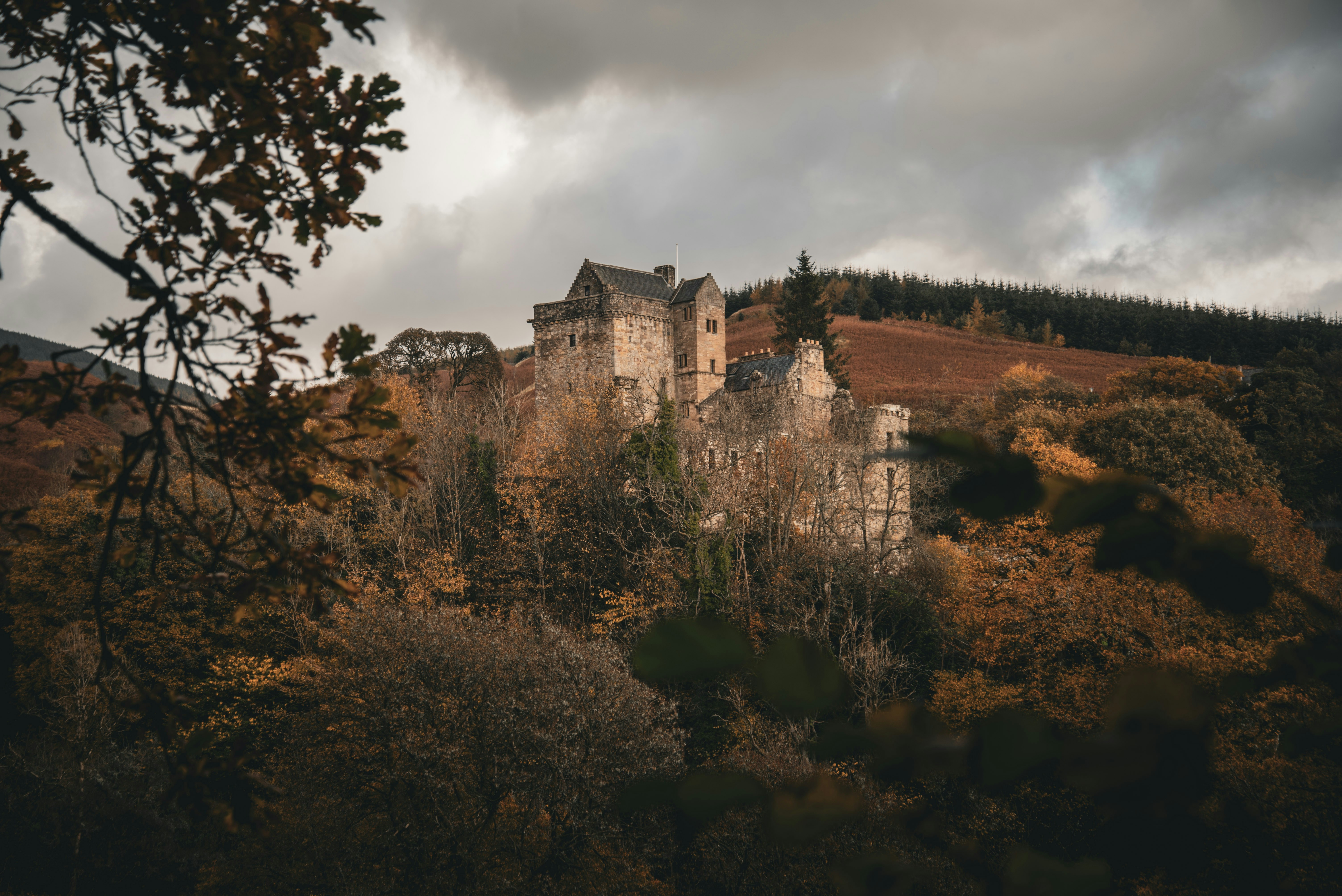 A castle sitting on top of a lush green hillside photo – Free Castle ...