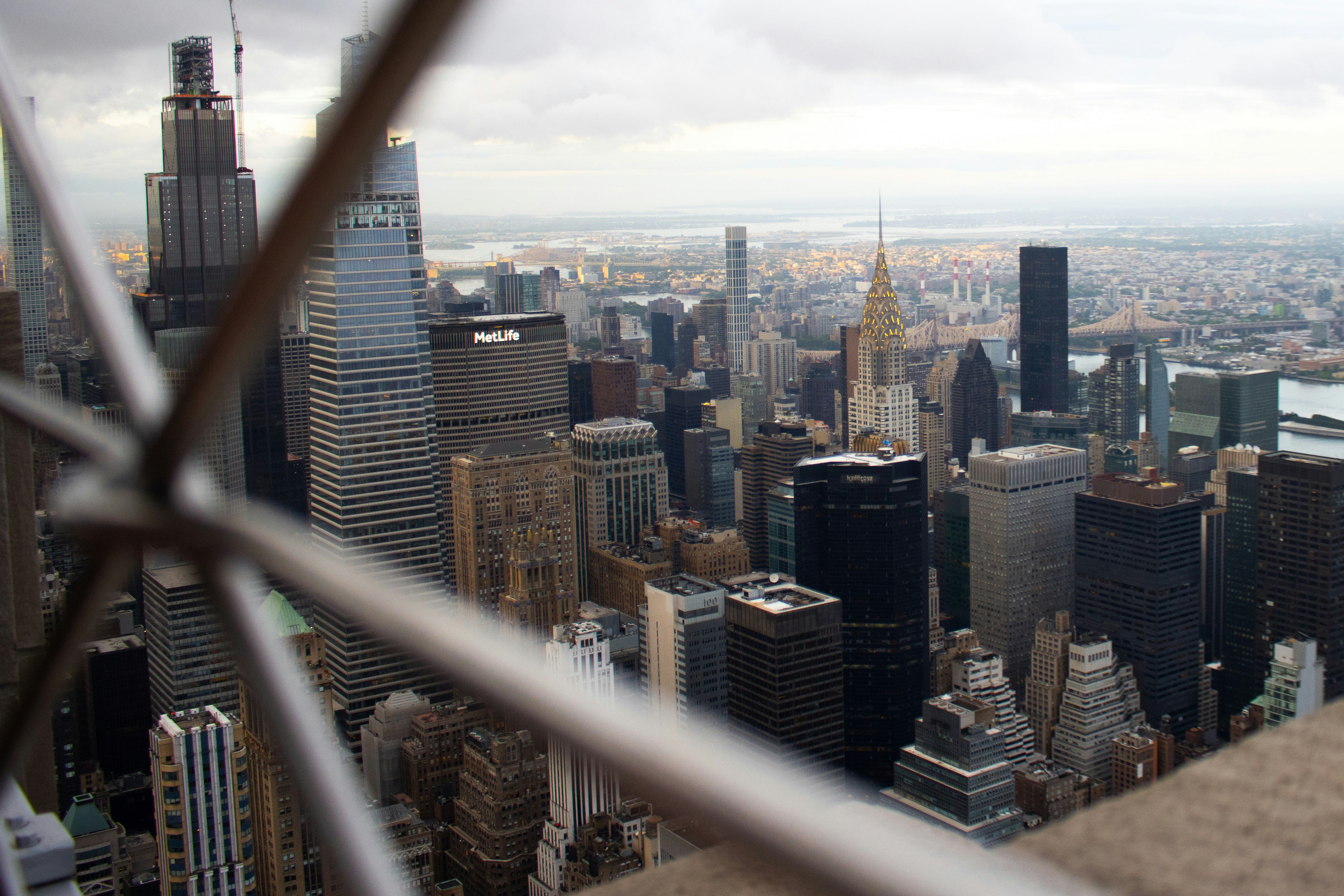 Framed skyline: steel rails cradle a cluster of Midtown skyscrapers beneath a clouded sky