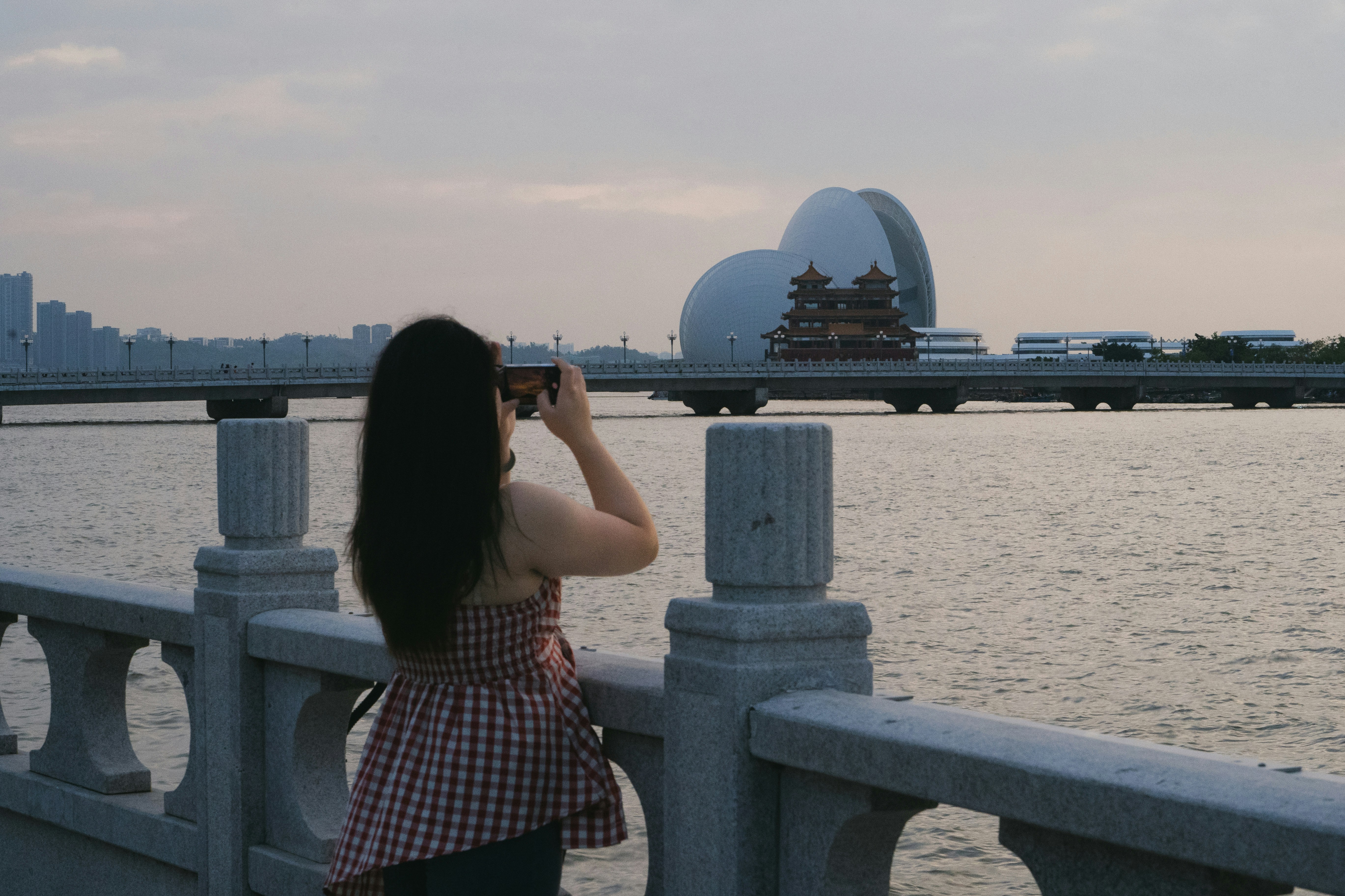 A woman standing on a bridge looking at the water photo – Free Girl ...