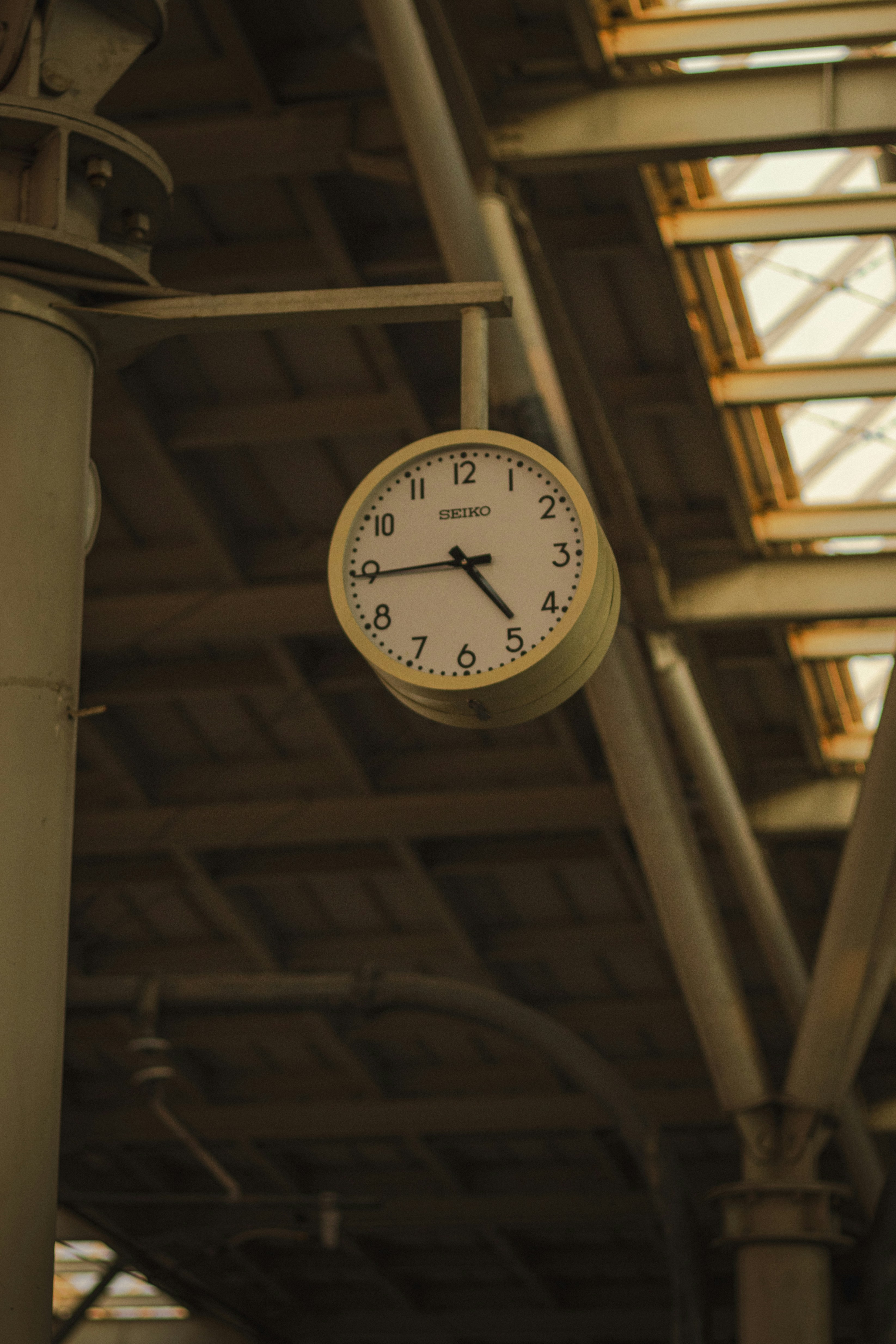 A clock hanging from the ceiling of a train station photo – Free Clock ...