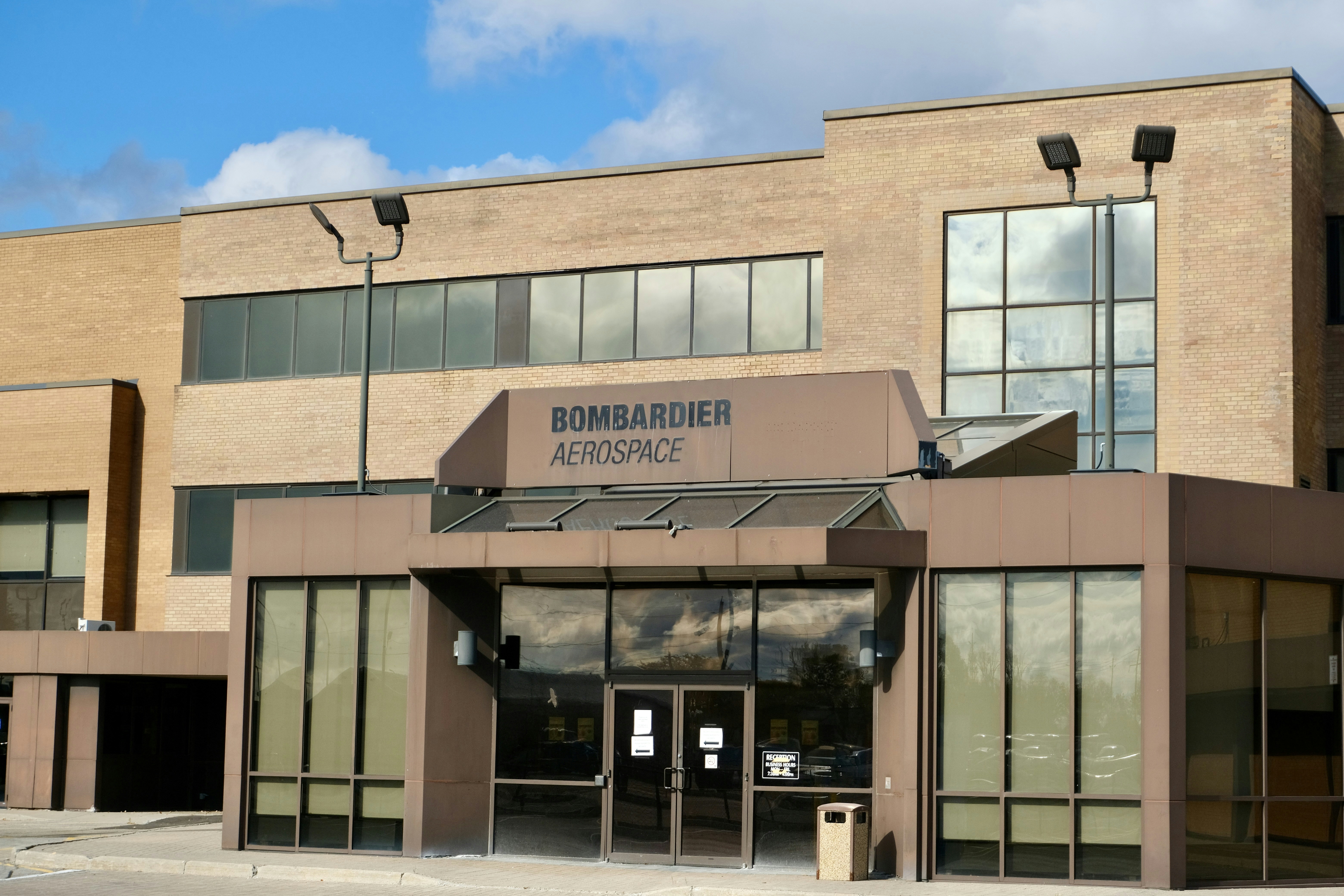 Contemporary office building with large windows reflecting a blue sky and clouds.