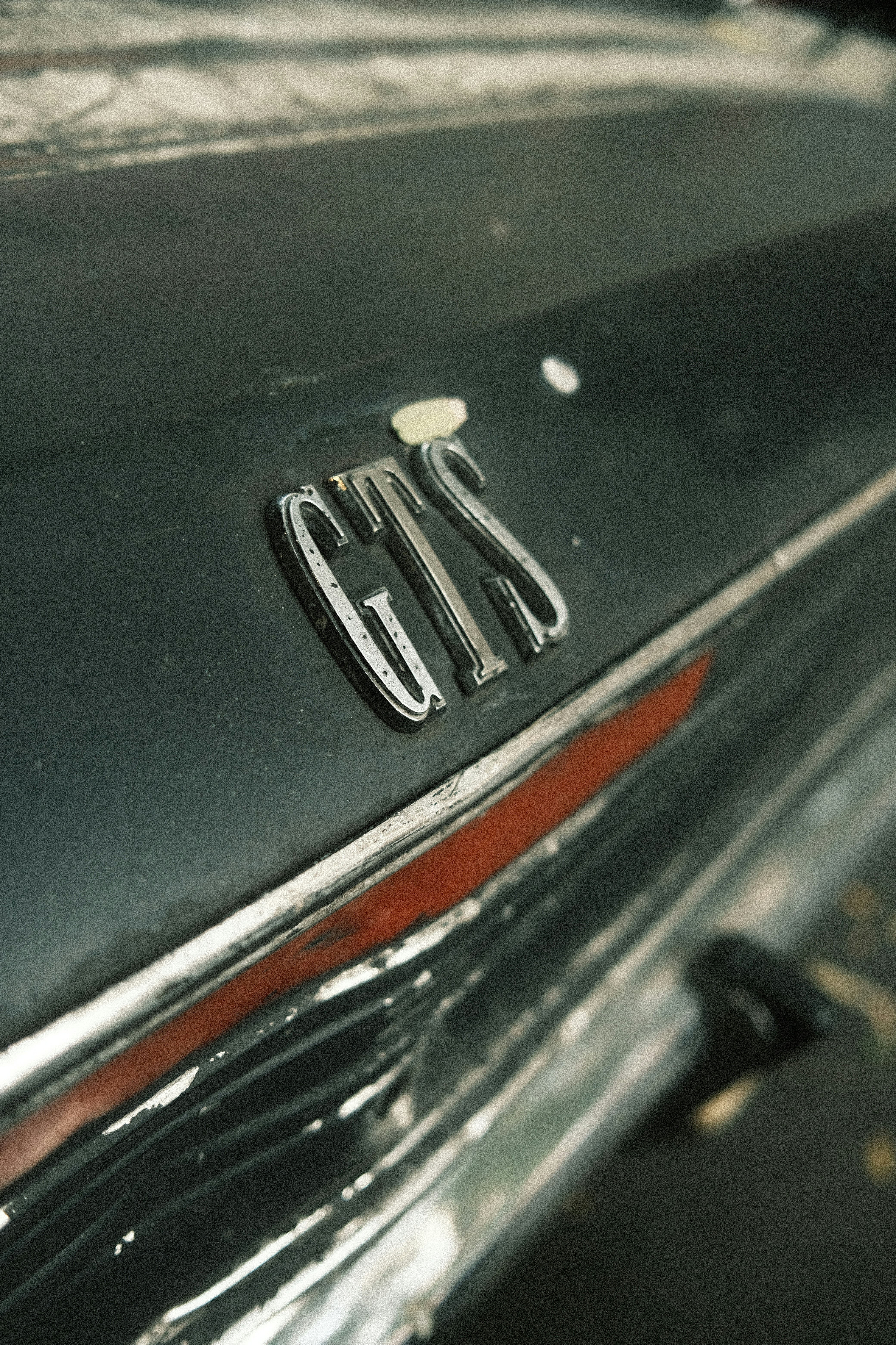 Patina-Glint: The GTS Emblem on a Weathered Classic Trunk