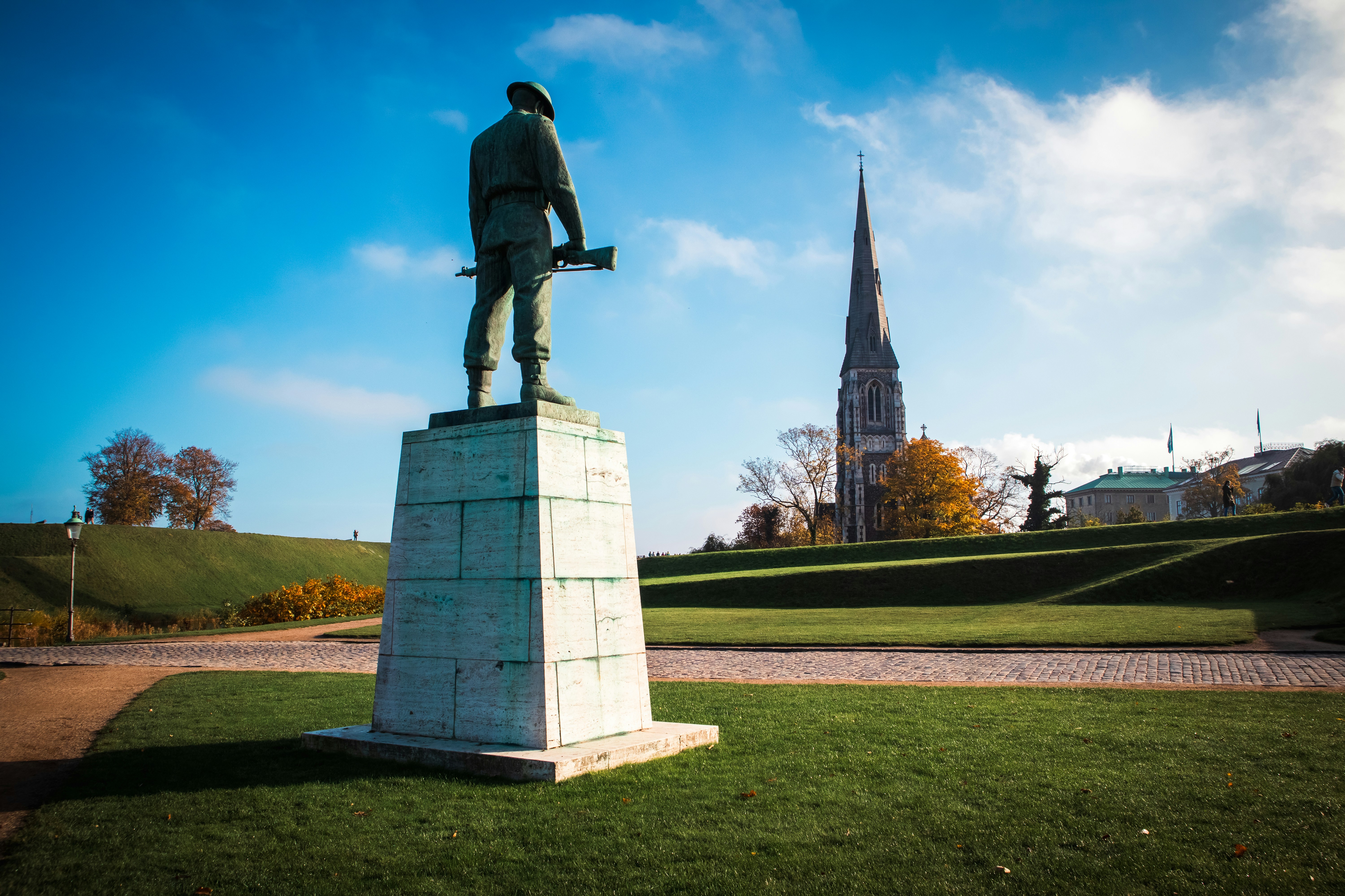 Autumn Light Over the Stone Sentinel: Statue with a Spire in the Distance