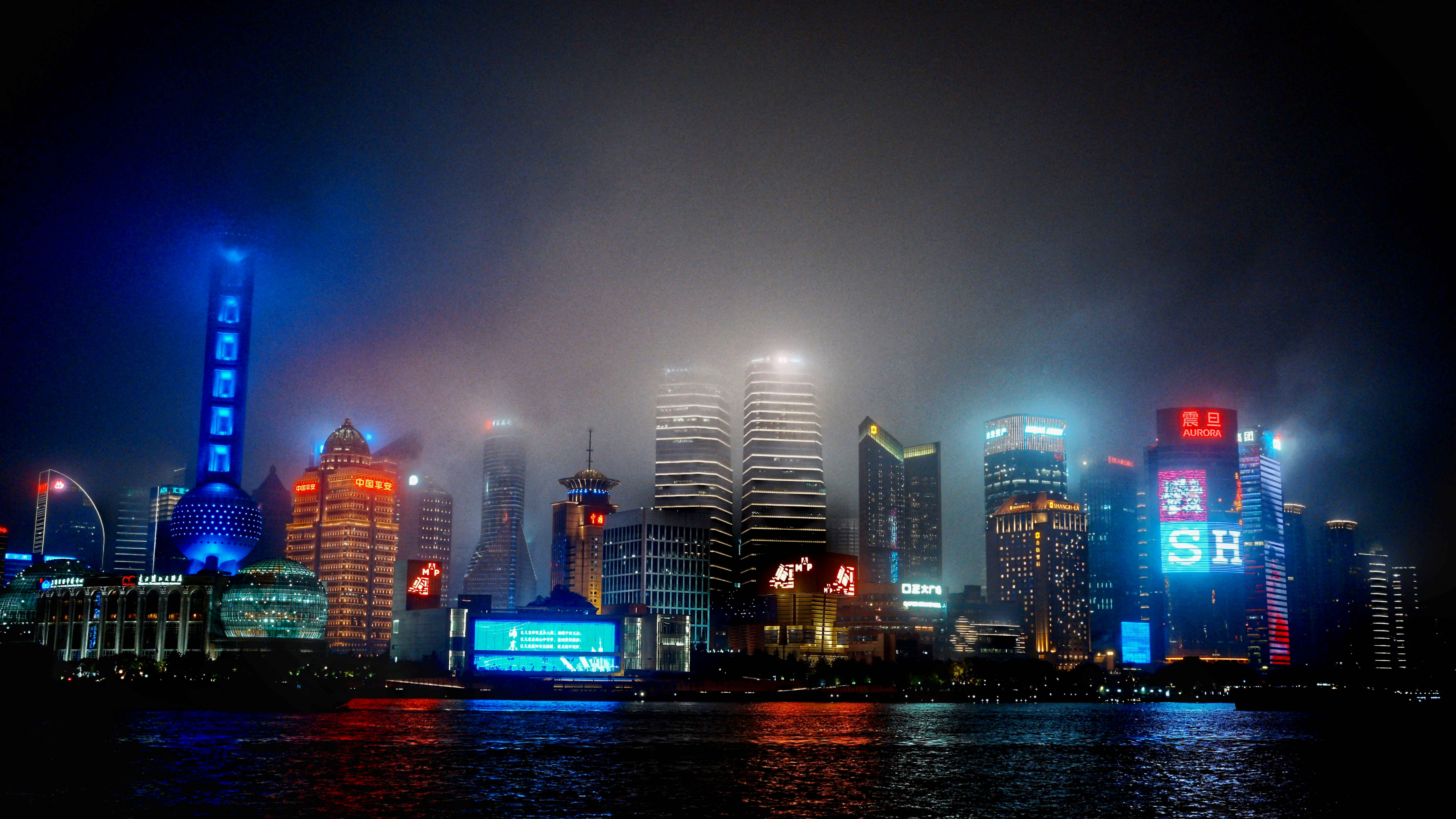 Mist-Framed Neon Skyline Over a Quiet River