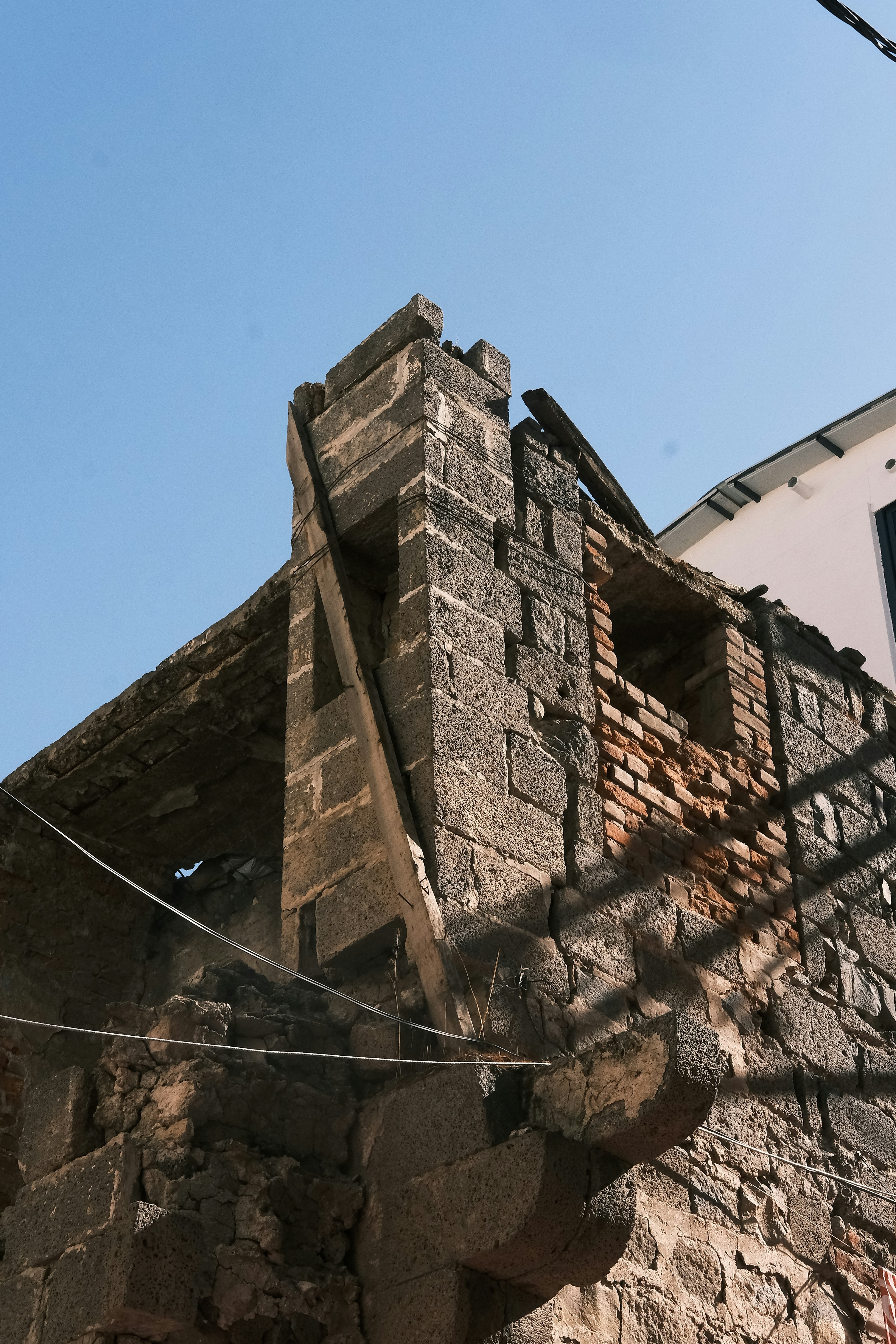 Weathered ruins of a stone building under a clear blue sky, showcasing the contrast between decay and resilience.