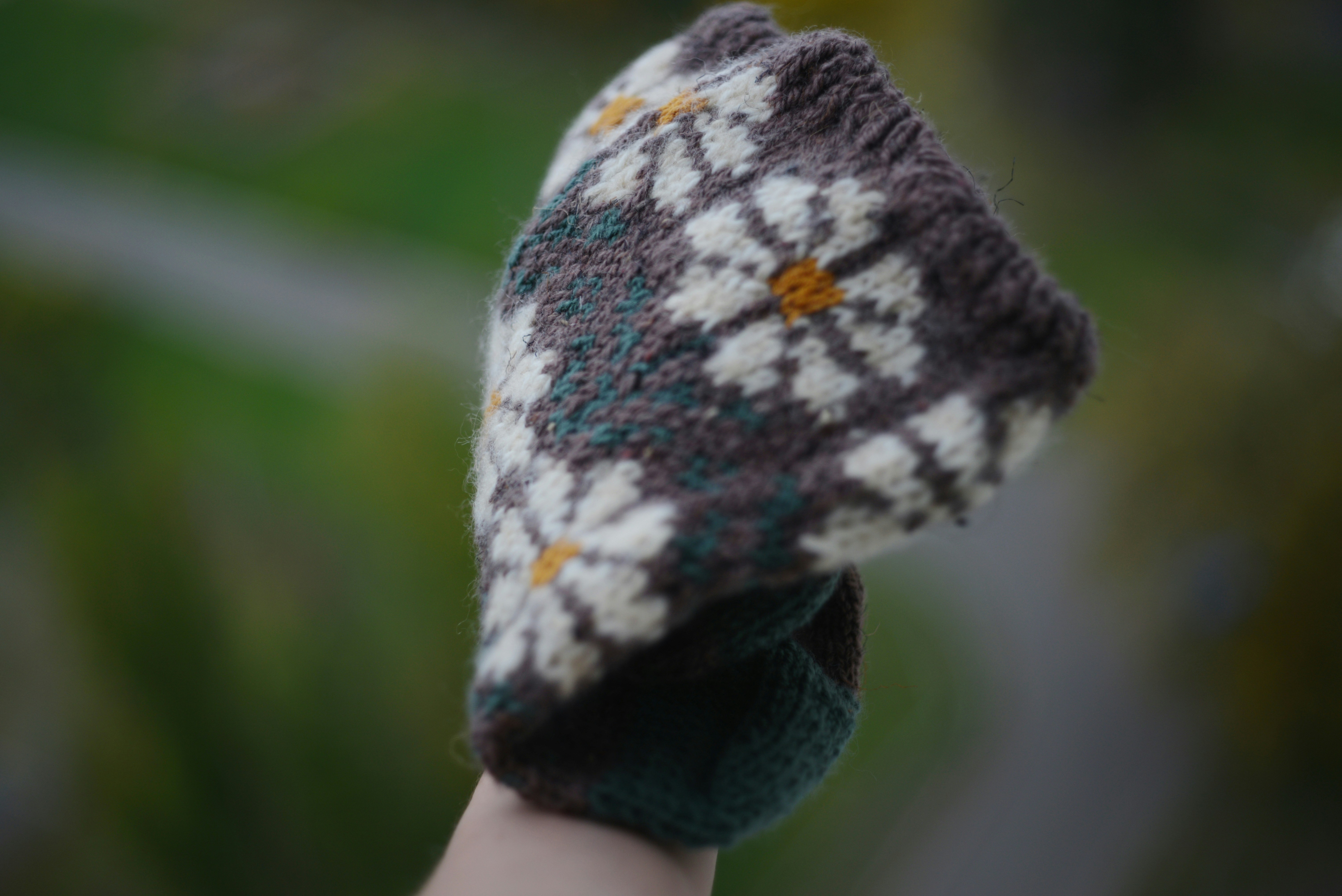 Close-Up of a Floral-Pattern Knit Glove Against a Soft Garden Bokeh