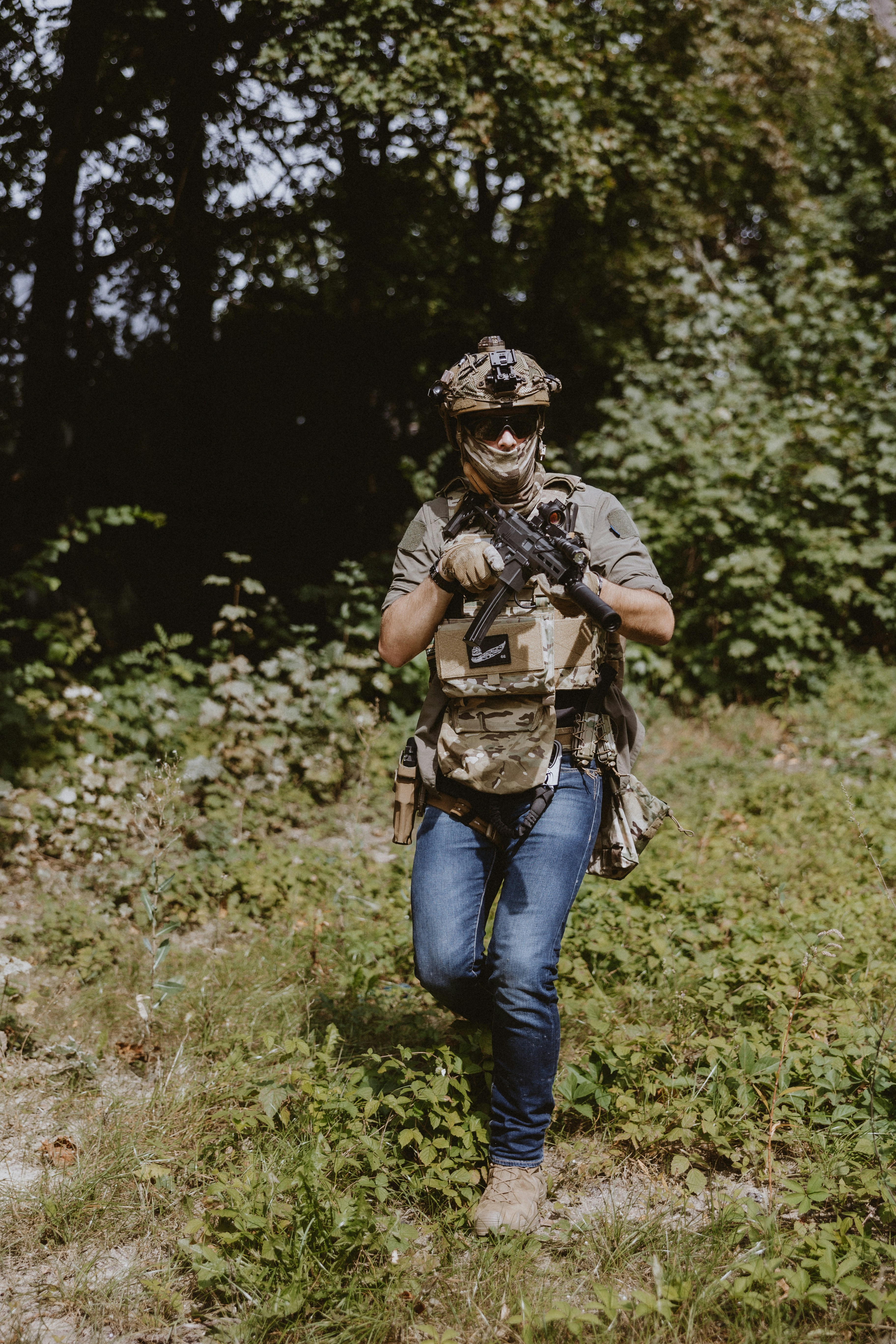 Soldier advancing through sunlit undergrowth with rifle at the ready