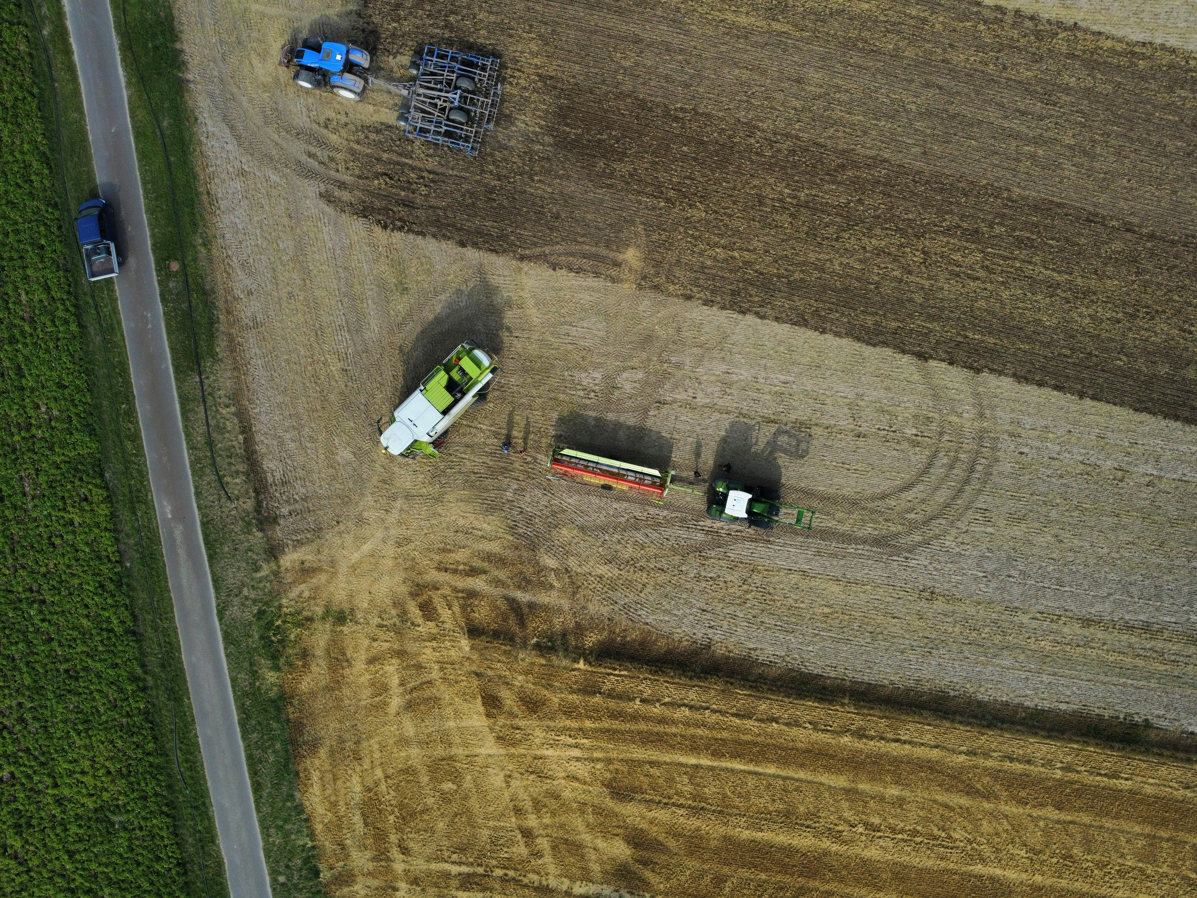 Aerial view showcasing agricultural machinery at work on a field, highlighting the coordination of farming equipment during harvest season.