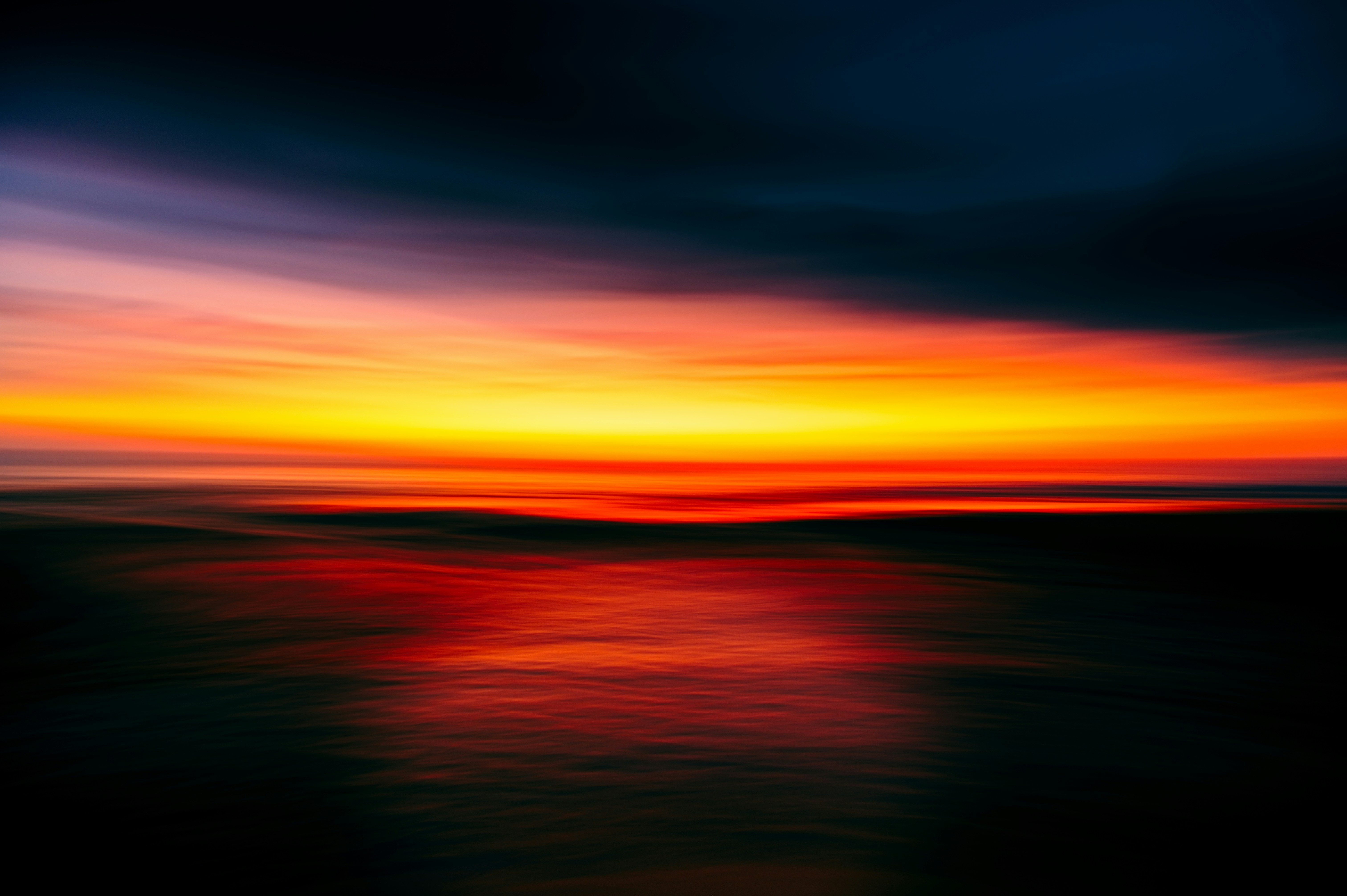 A blurry photo of a sunset over a body of water photo – Free Horizon ...
