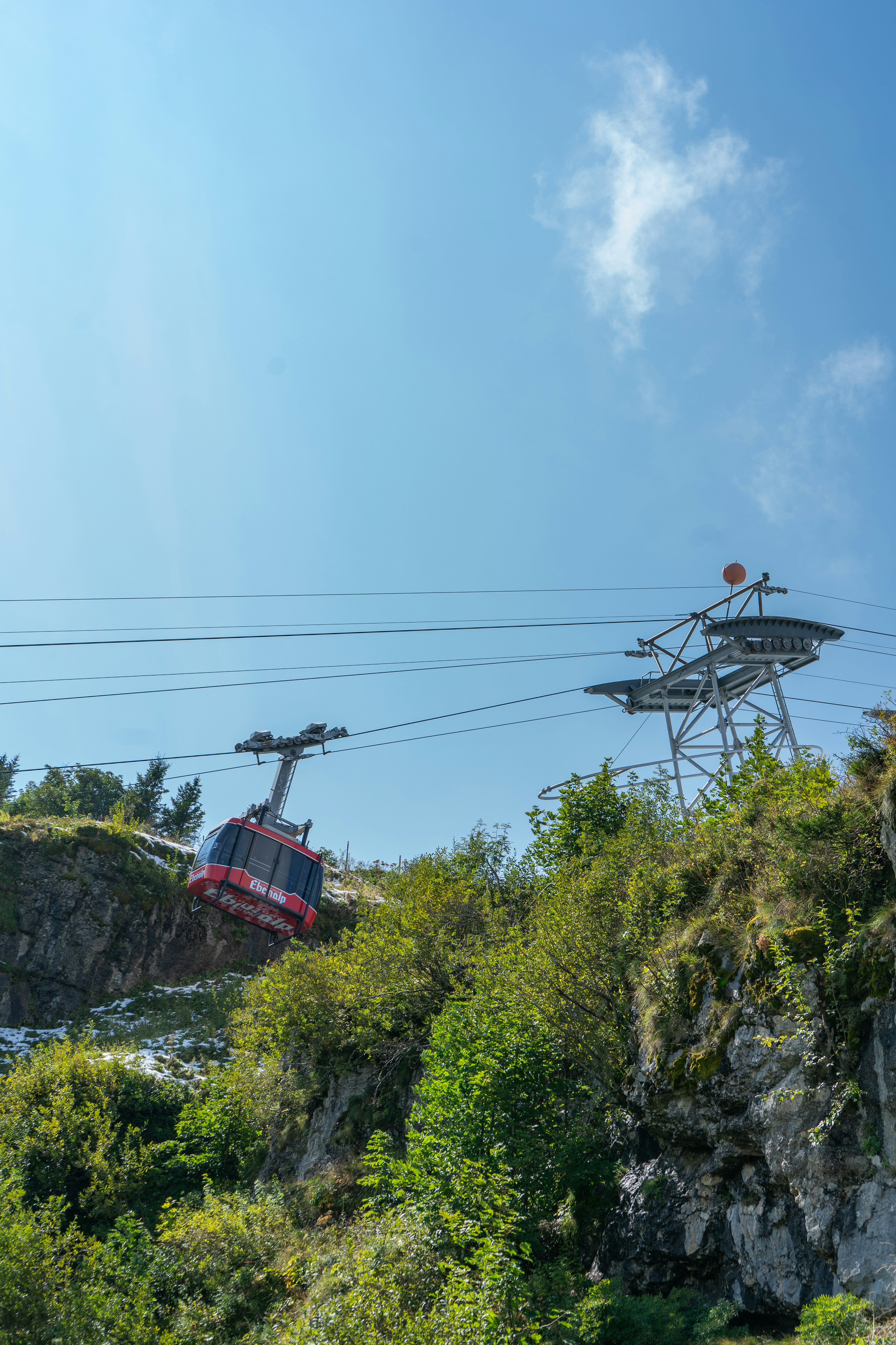 Red Gondola Skimming a Lichen-Covered Ridge Beneath a Pristine Blue Sky