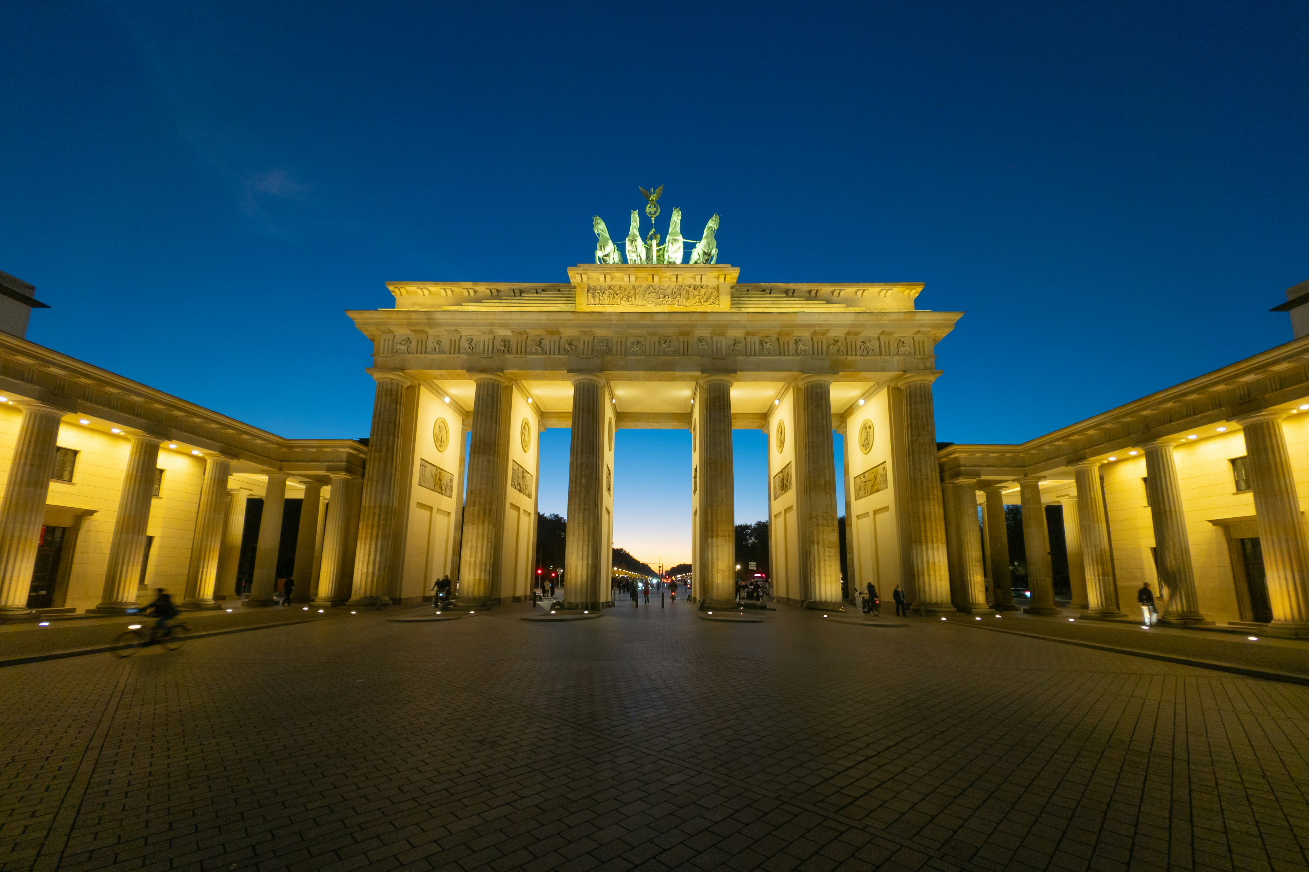 The Brandenburg Gate stands majestically illuminated against the twilight sky, showcasing its neoclassical architecture and historical significance.