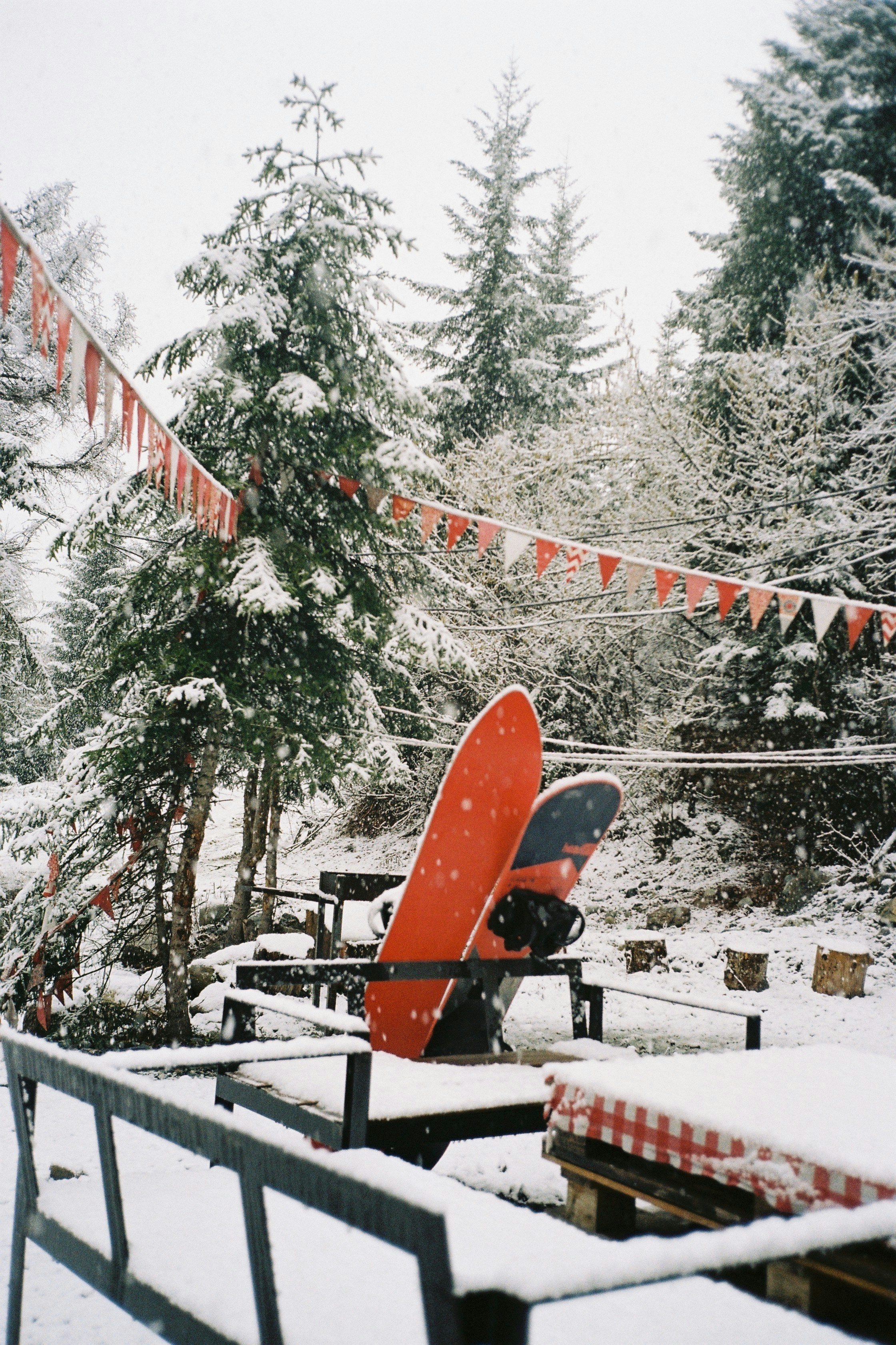 Orange Snowboard Among Snow-Dusted Pines and Festive Banners
