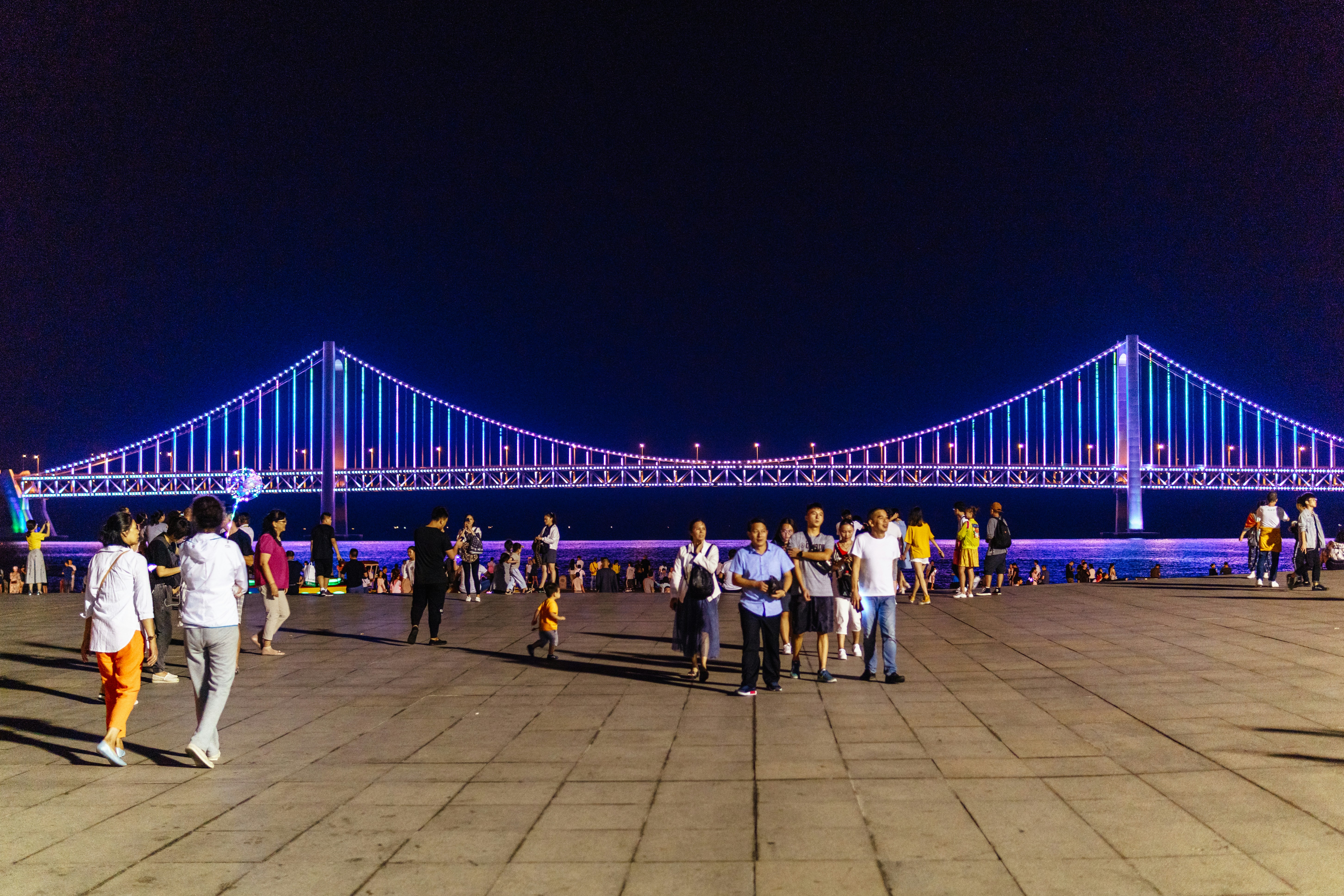 A group of people walking across a bridge at night photo – Free Travel ...