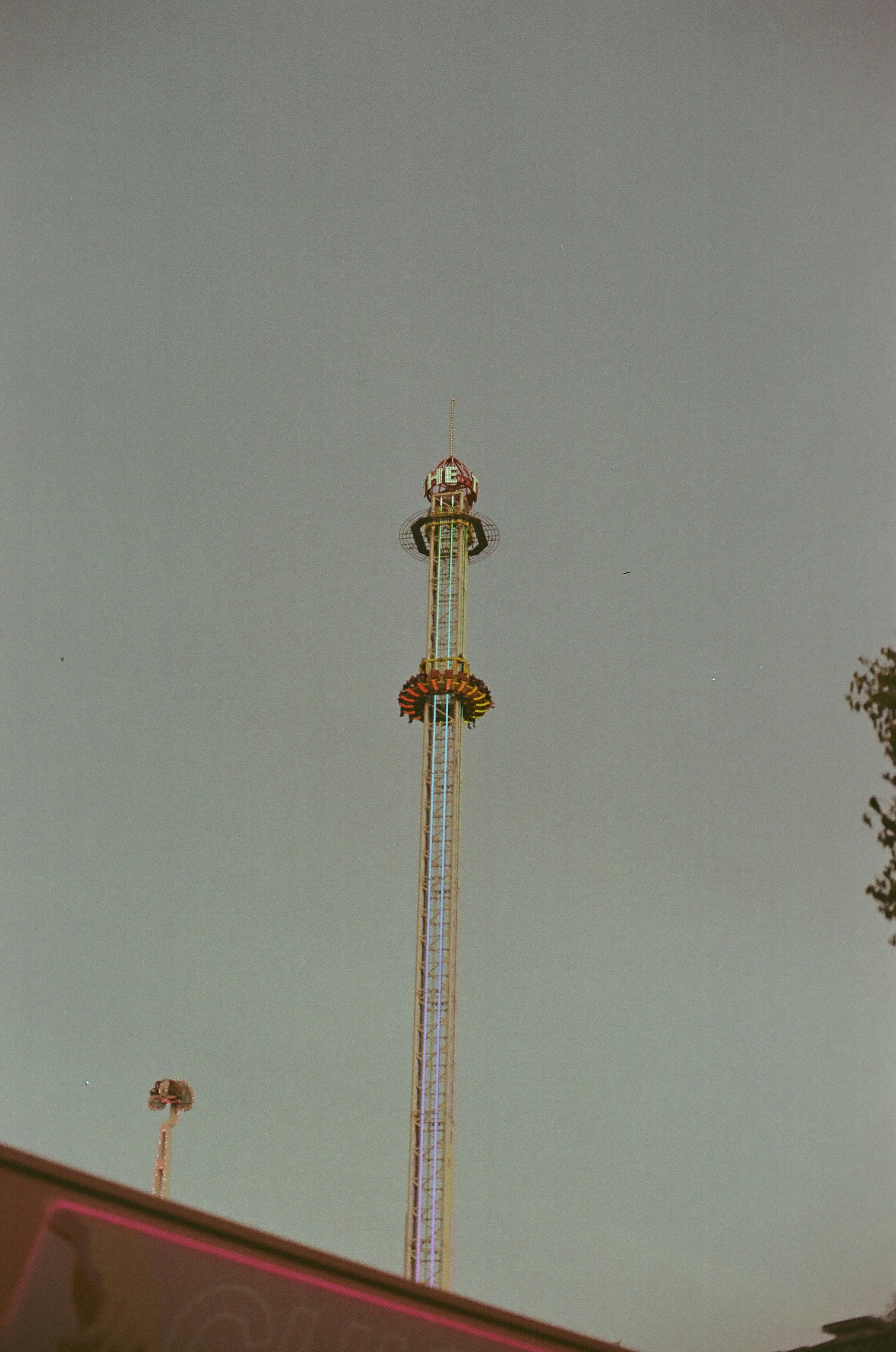 A tall tower with a carnival ride in the background photo – Free ...