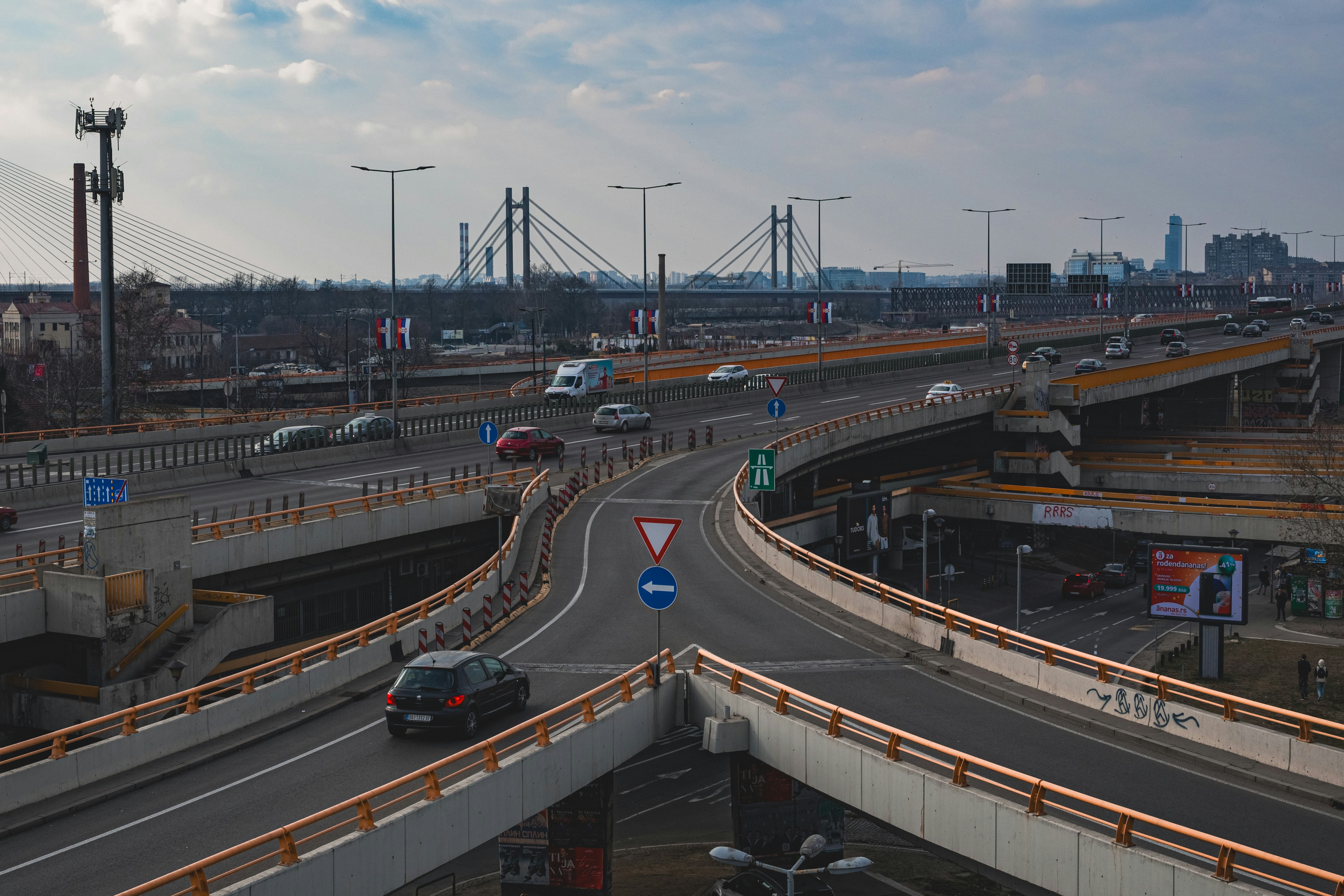 Intricate network of overpasses and highways bustling with vehicles under a cloudy sky.