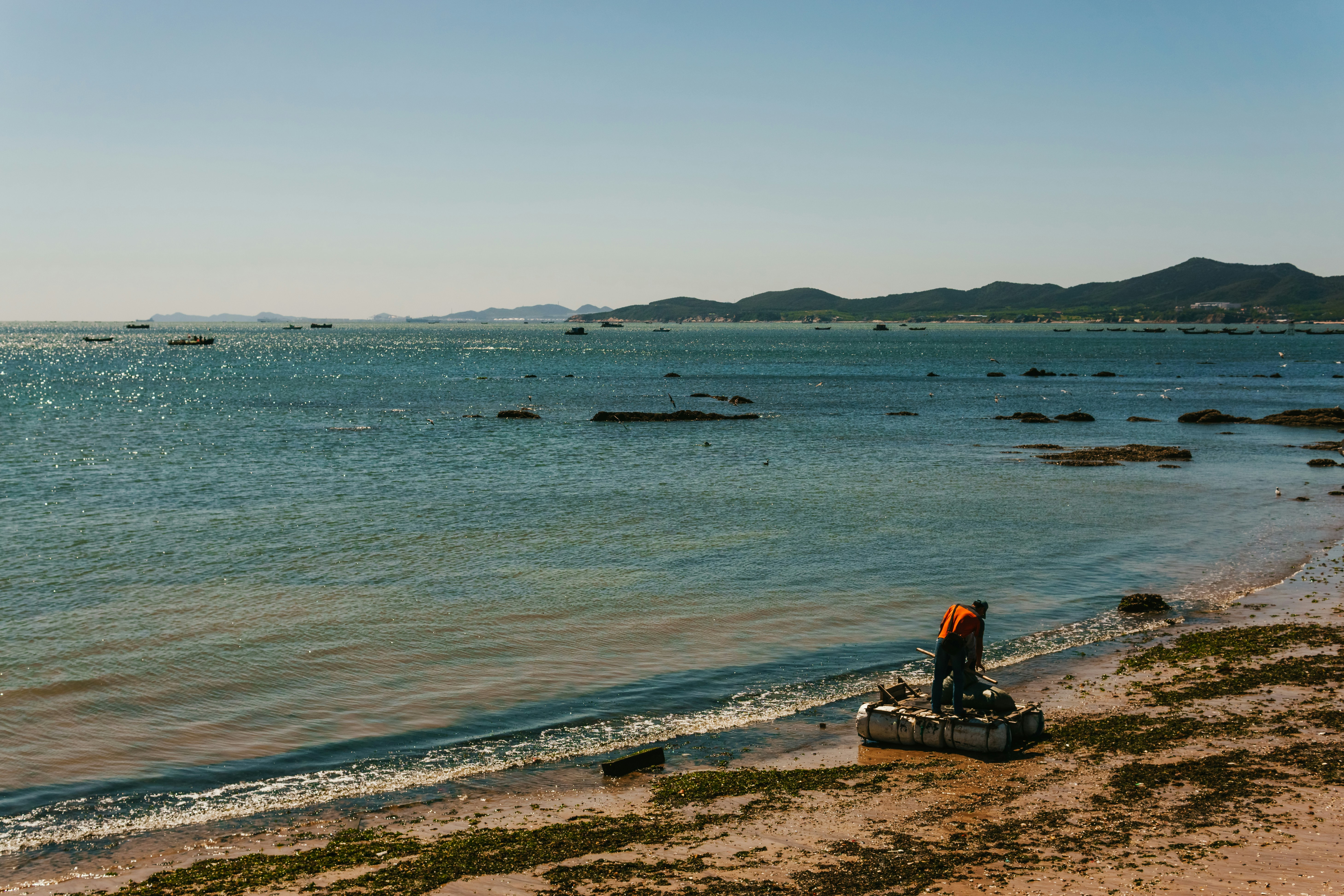 A person standing on a beach next to the ocean photo – Free Dalian ...