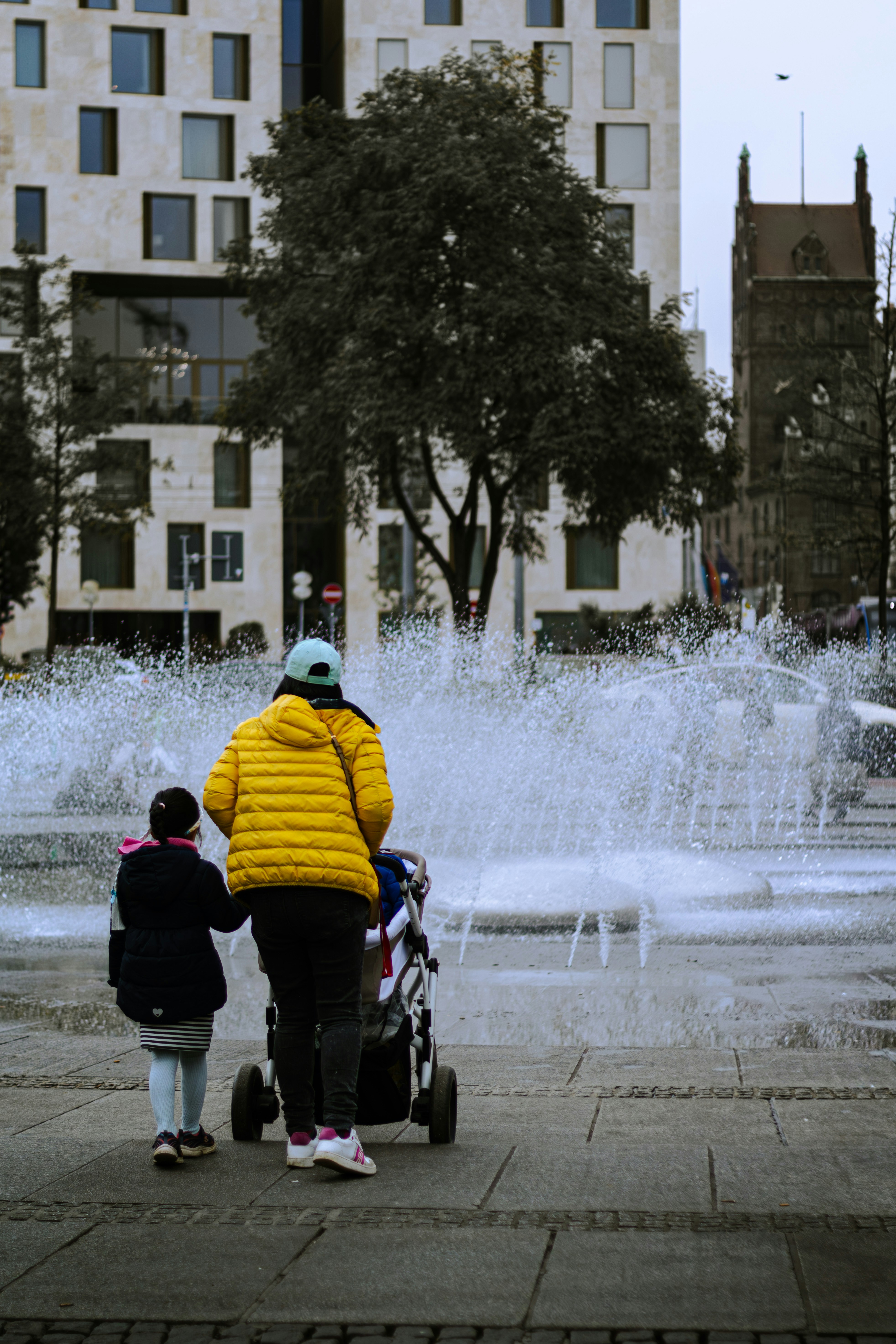 Yellow Anorak by the Fountain: A City Moment with Parent and Child