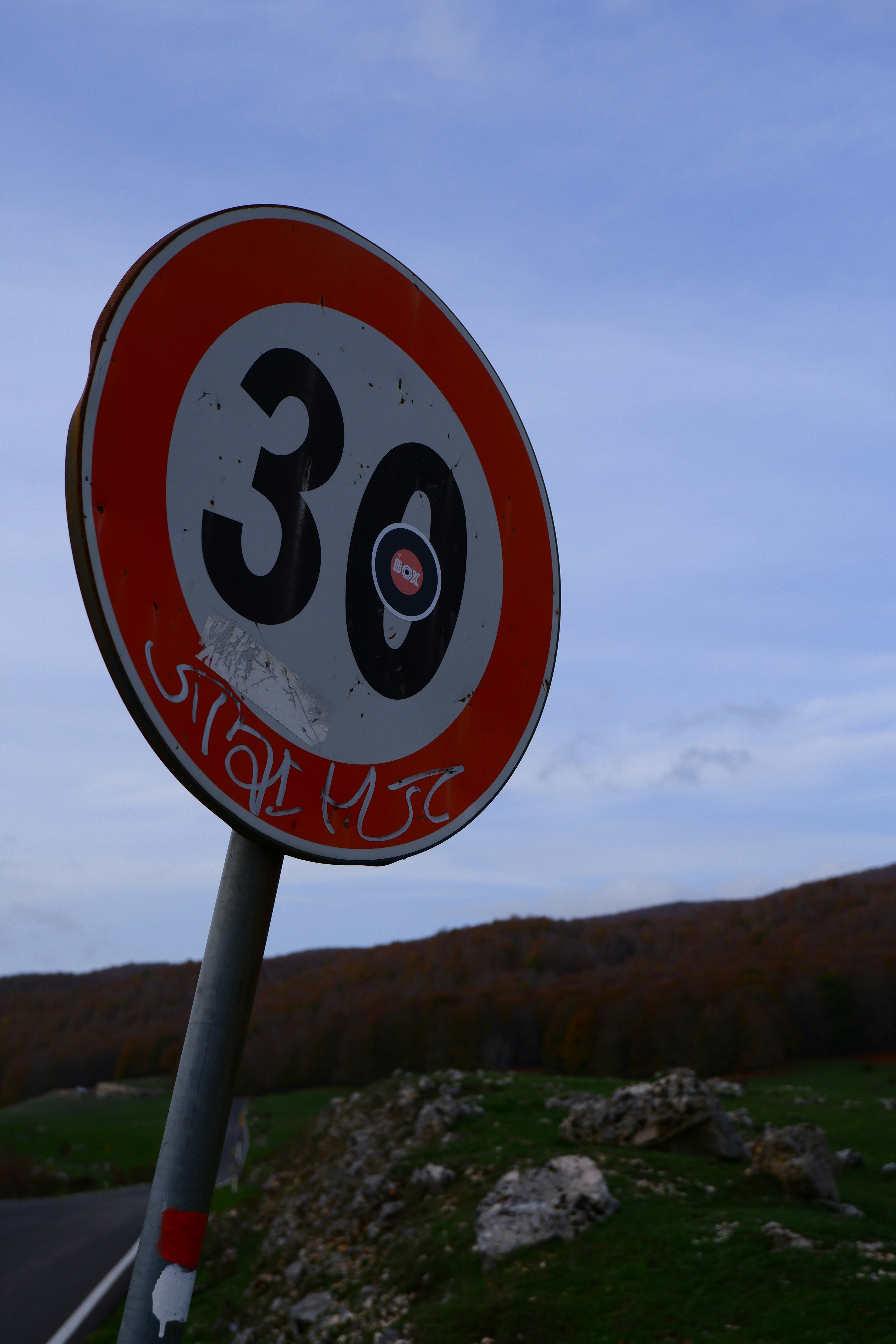 Tilted 30 Sign: Graffiti, Grass, and a Quiet Country Road
