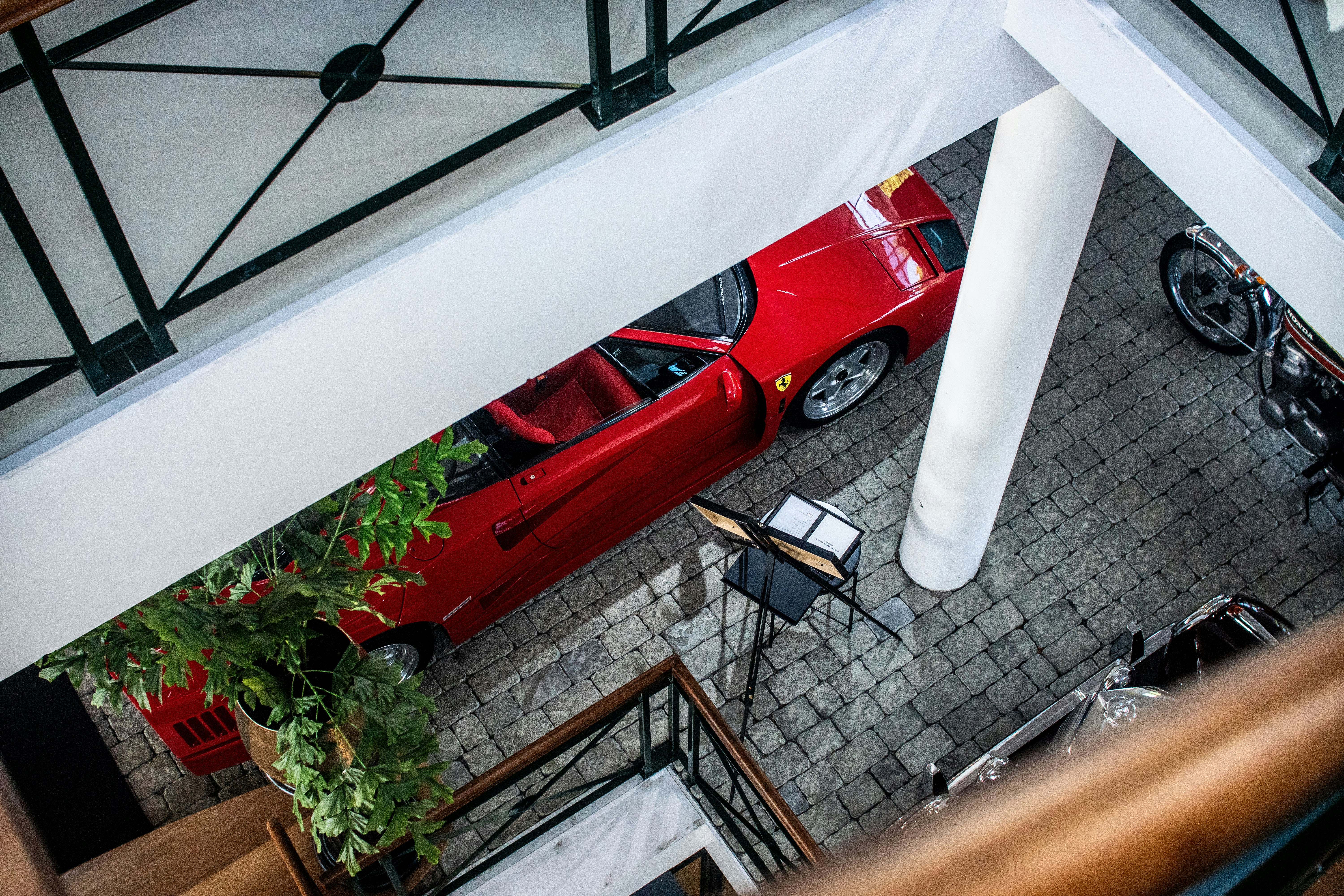 Crimson Sports Car Framed by Glass Atrium Geometry