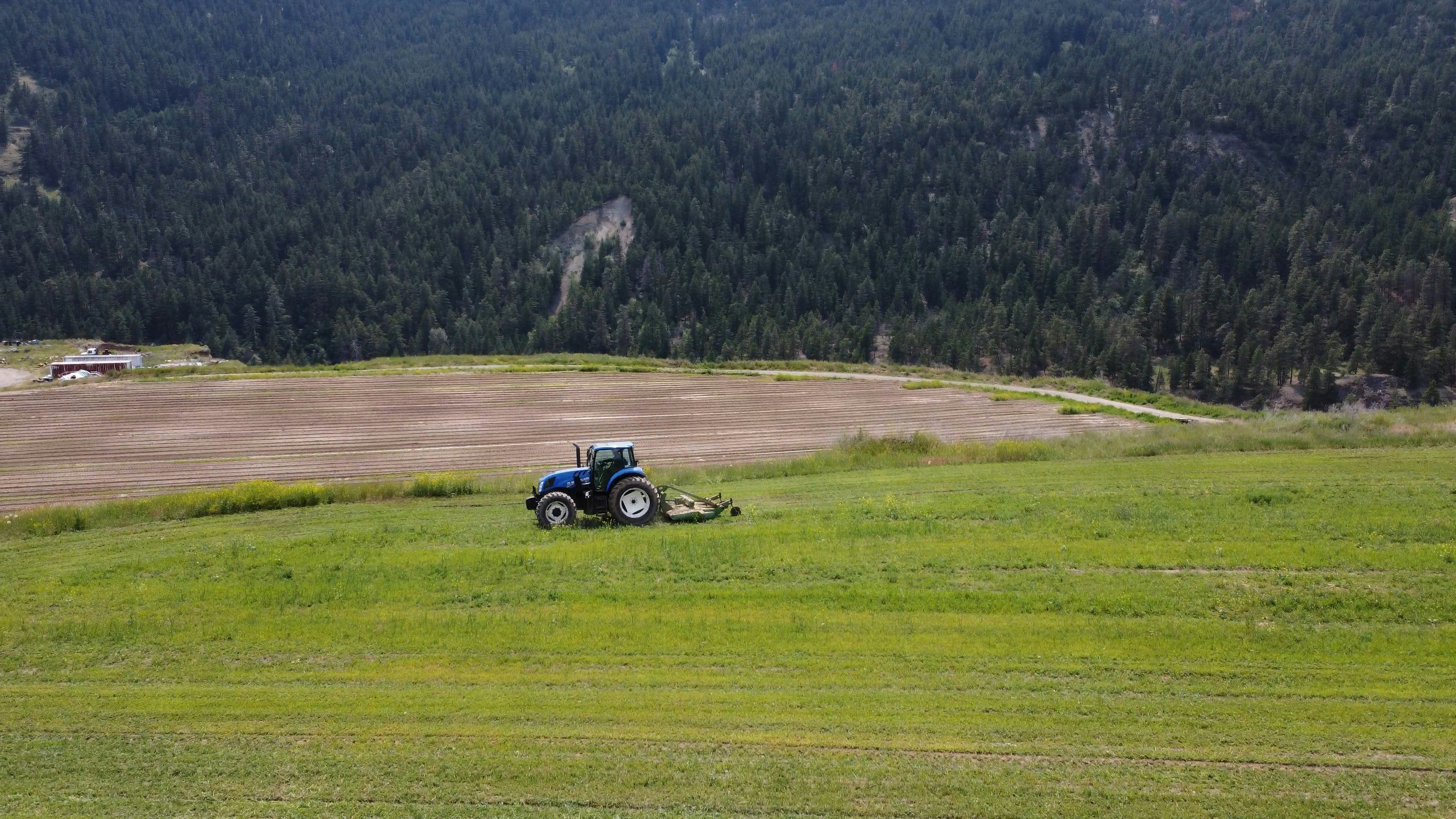 A tractor in a field with mountains in the background photo – Free ...