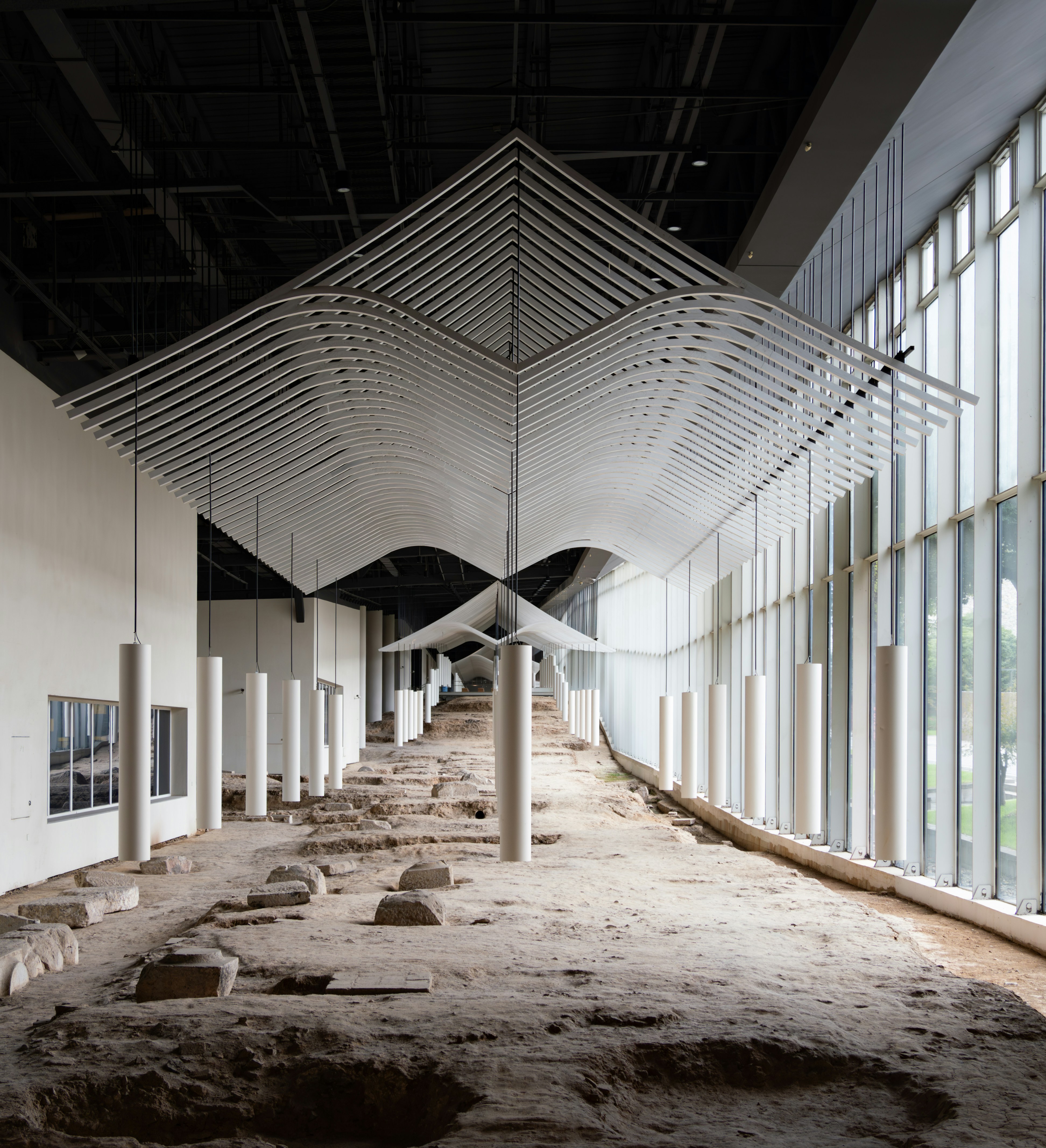 Echoes of Light Beneath a Suspended Wave Canopy in a Dusty Gallery Atrium