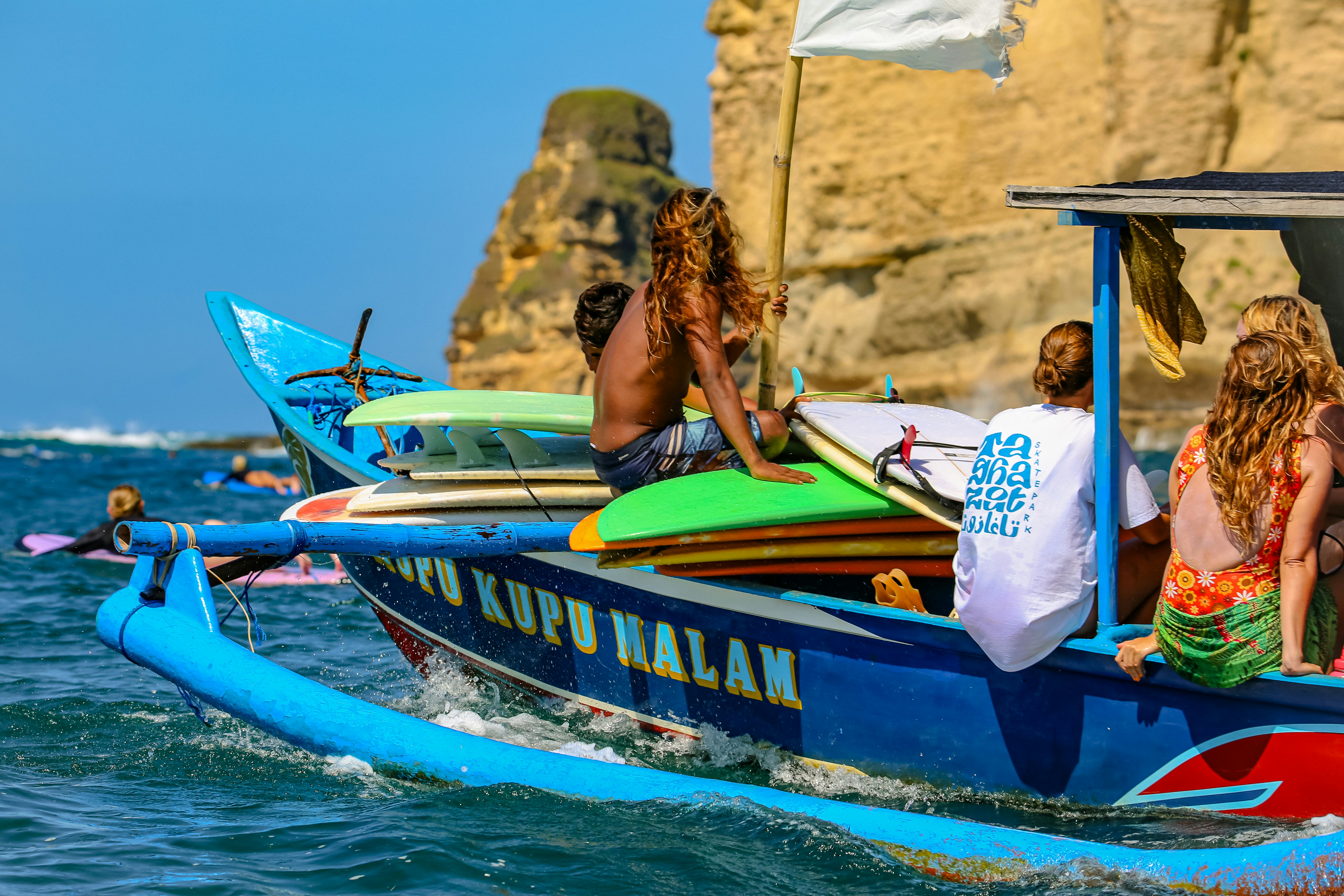 Bright Outrigger Wake: Passengers and Surfboards Ride Turquoise Seas