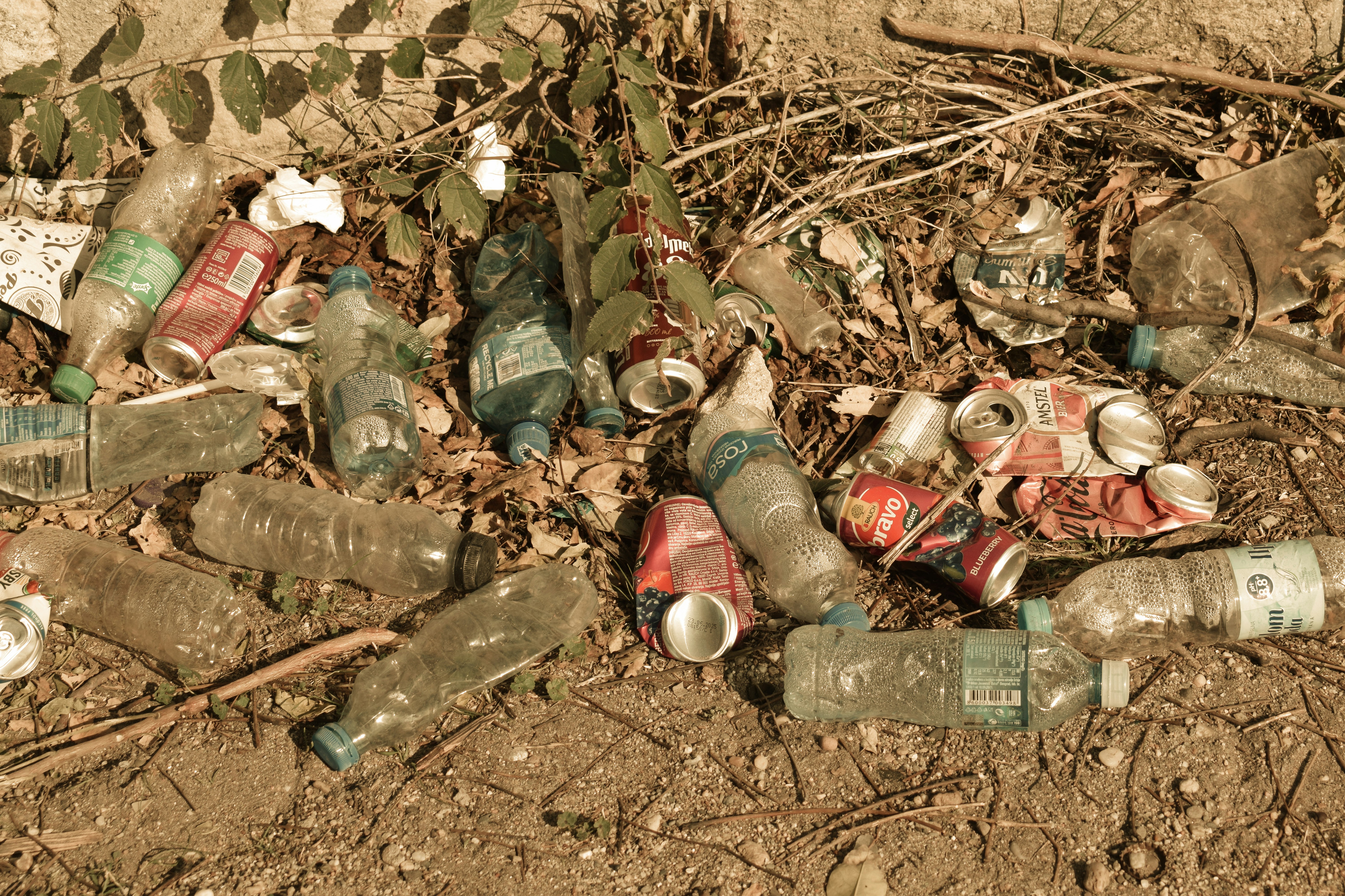A pile of discarded bottles and cans on the ground photo – Free Trash ...