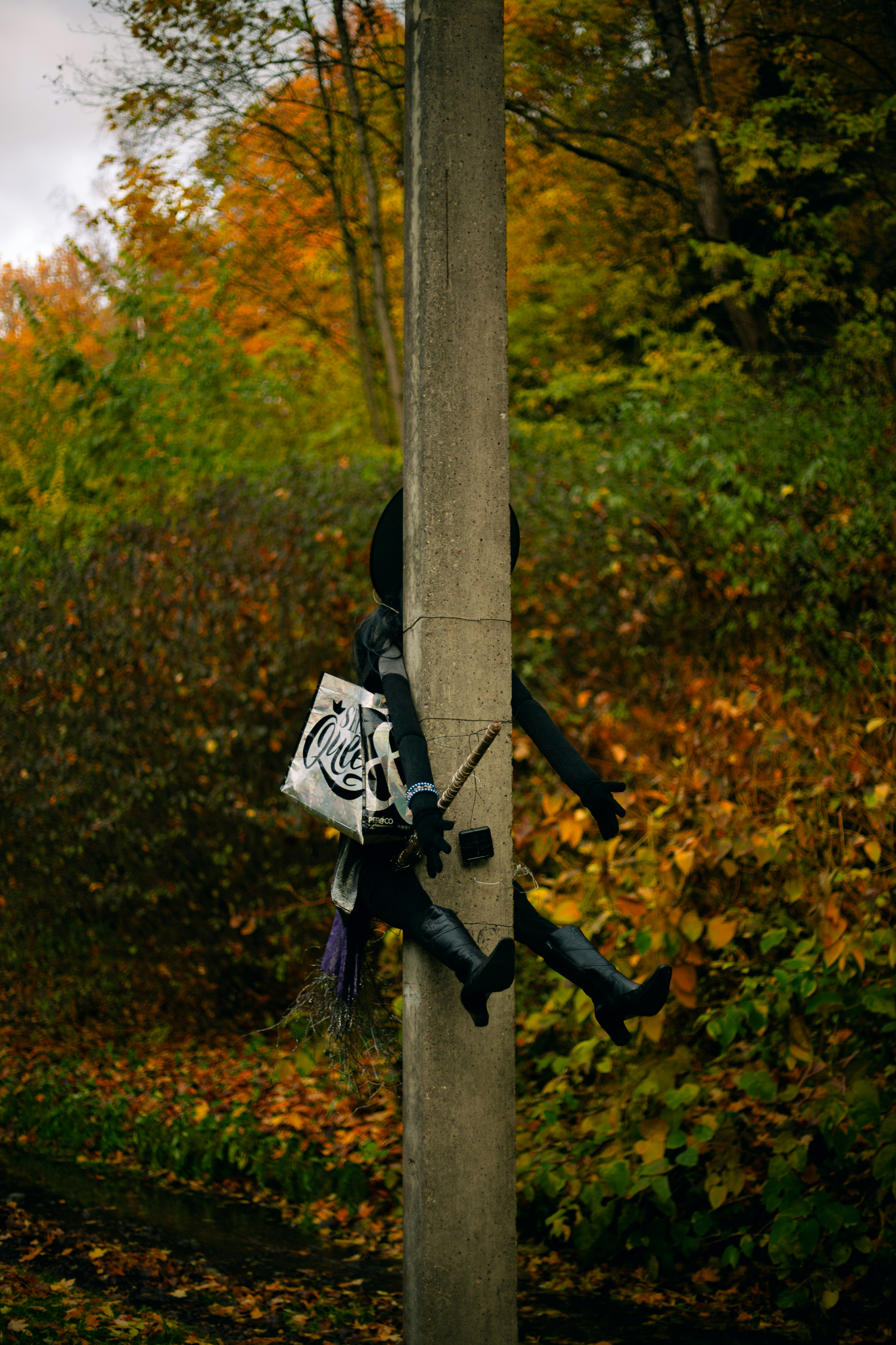 Masked Figure Climbing a Lamppost Amid Autumn Foliage