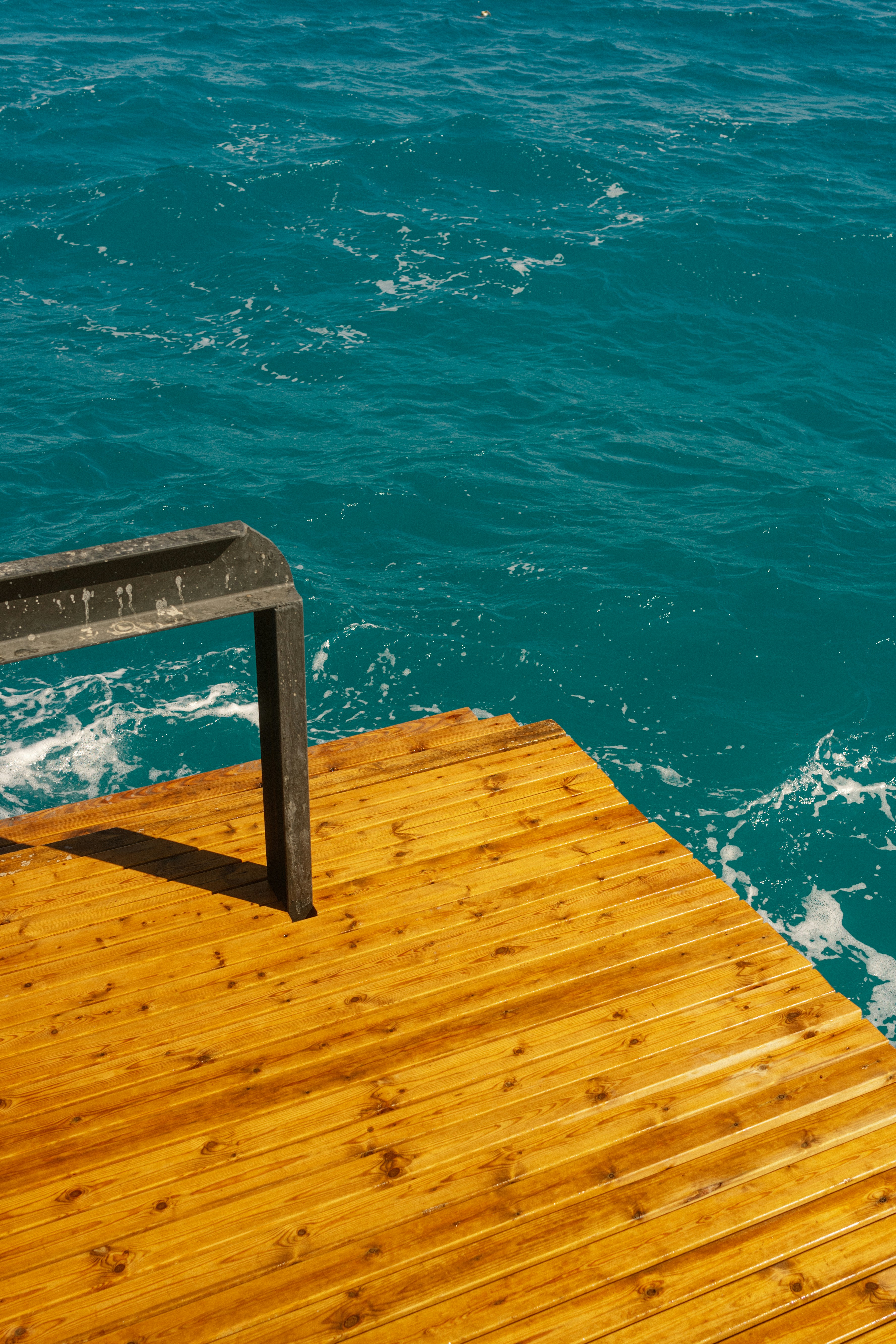 Sunlit Cedar Planks Edge Into a Turquoise Sea: A Quiet Pier Moment