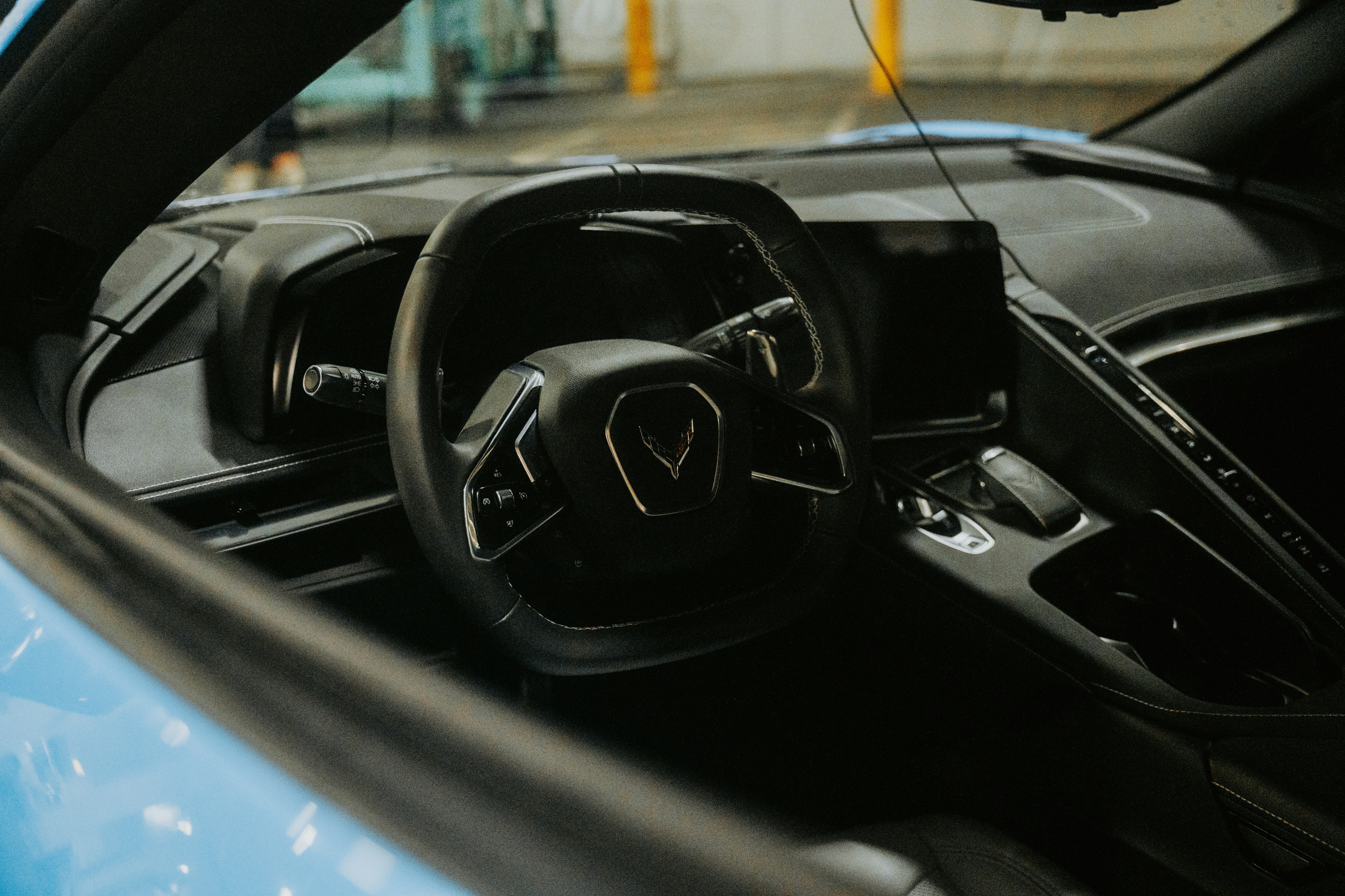 Blue Cockpit Focus: Angular Steering Wheel and Digital Dash in a High-Performance Interior