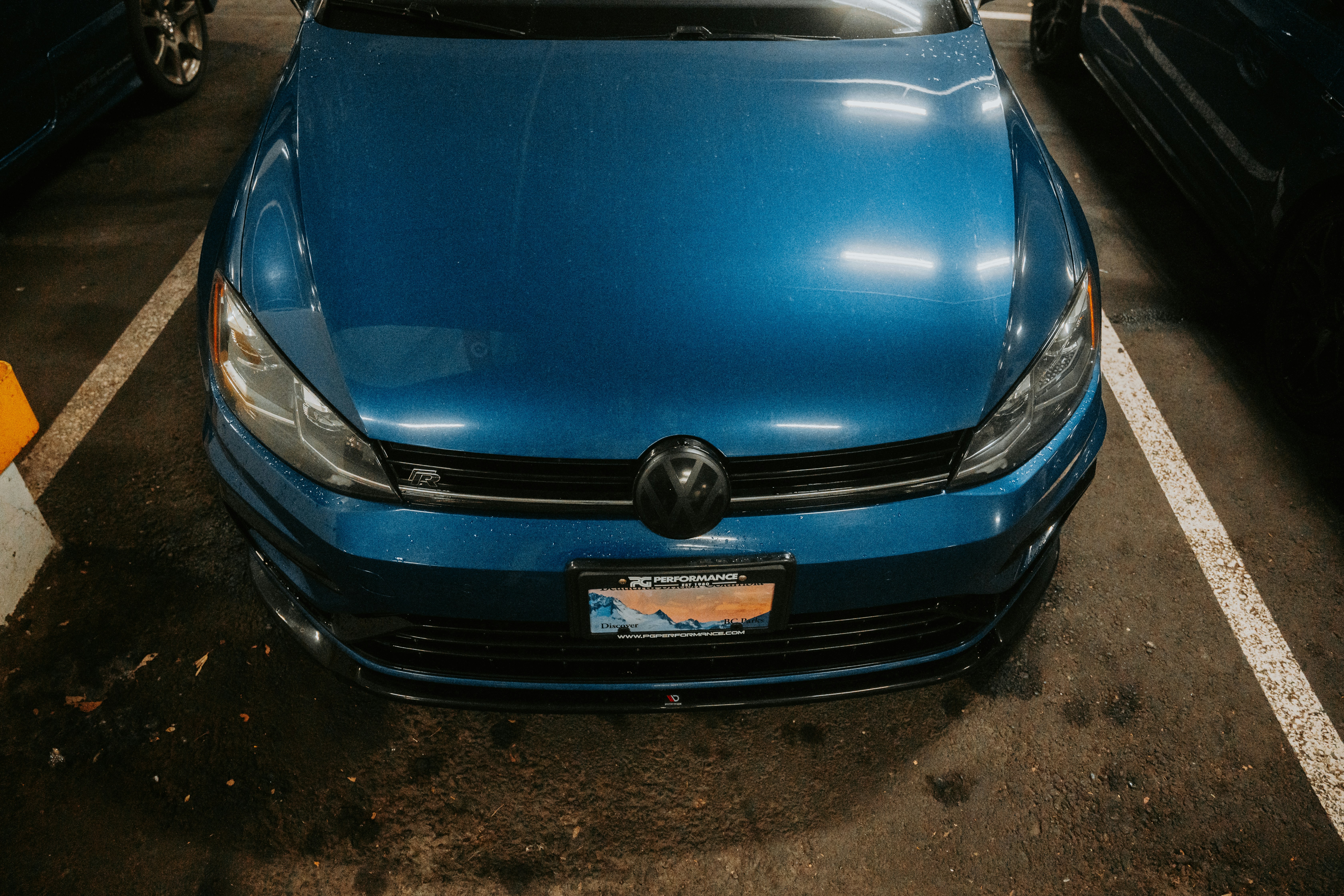 Blue Volkswagen in a Quiet Parking Garage: Geometry, Light, and a Centered Front View