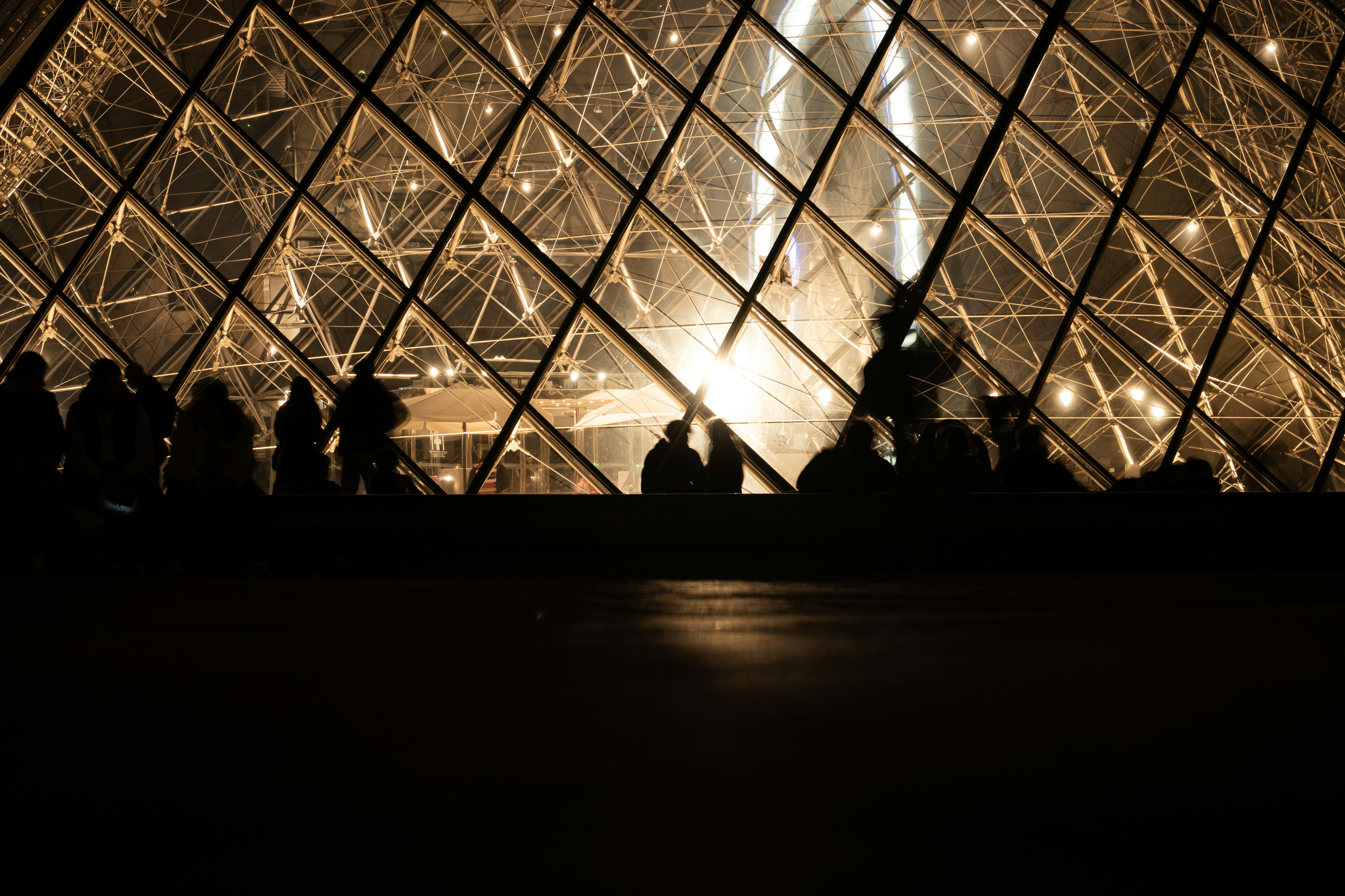 Silhouetted Crowds Under the Louvre Pyramid's Diamond Glow