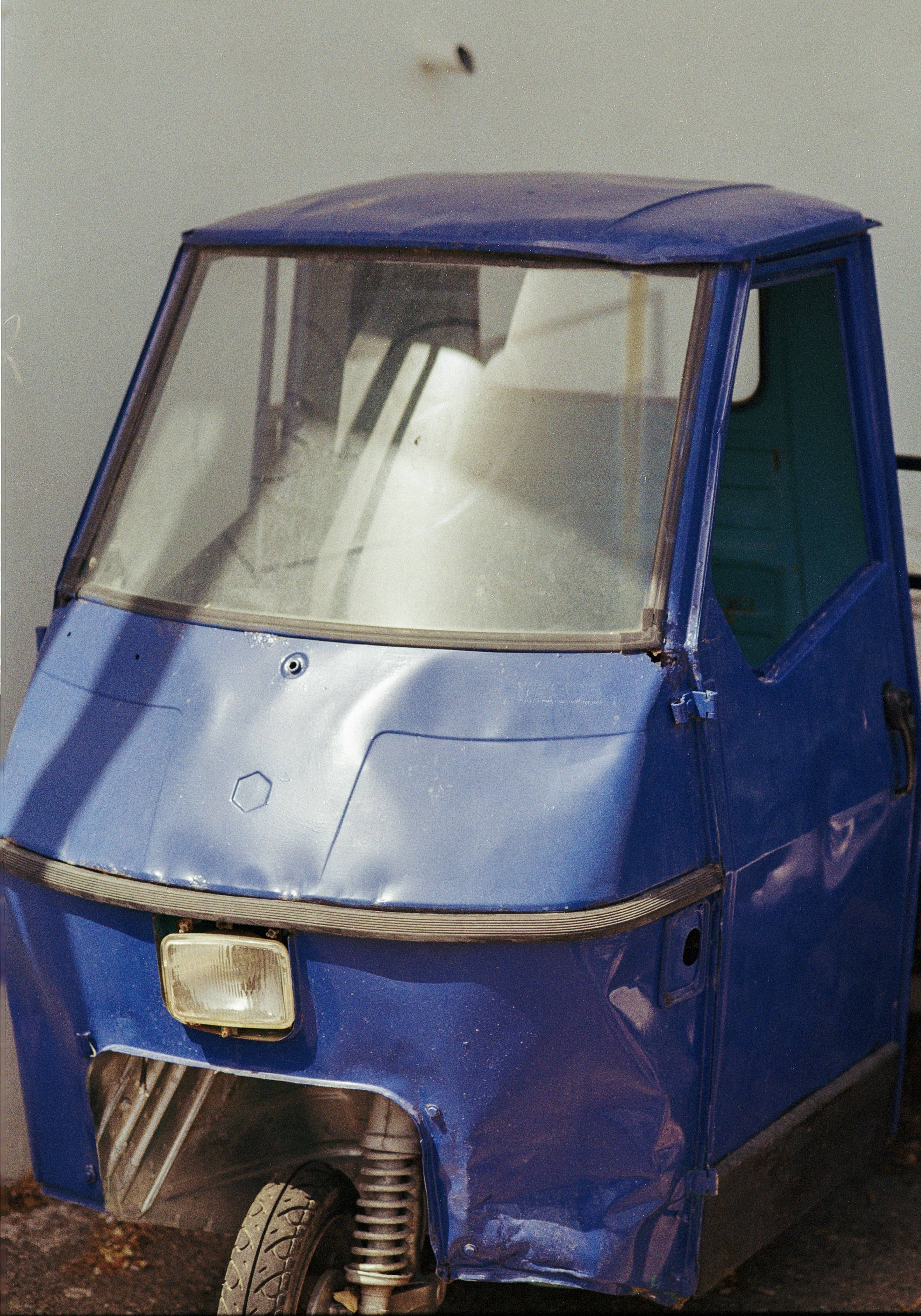 Blue Front-Cab Portrait: A Weathered Three-Wheeled Work Vehicle